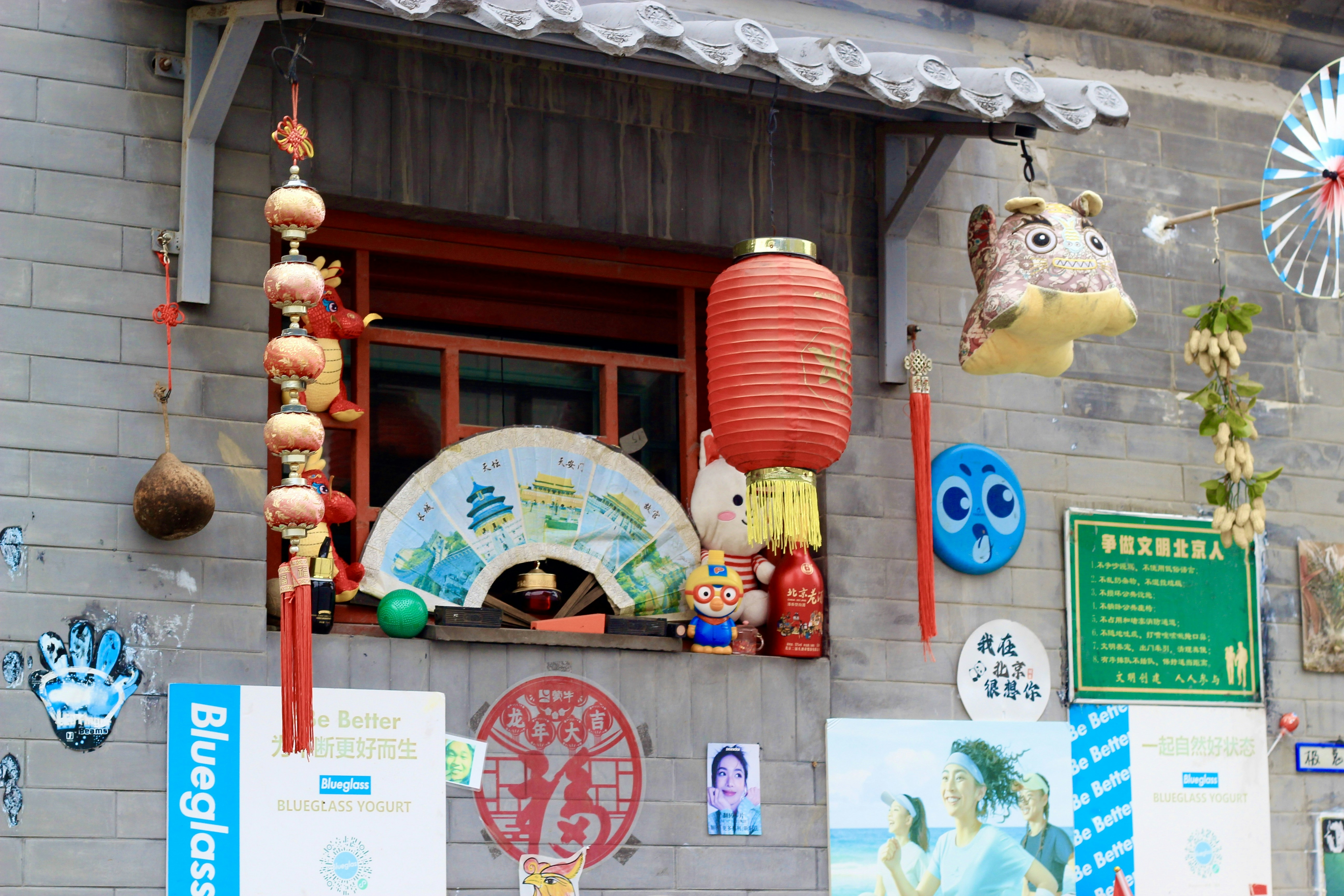 Red Lantern Ferrying Wishes Above a Wall of Colorful Street Ornaments
