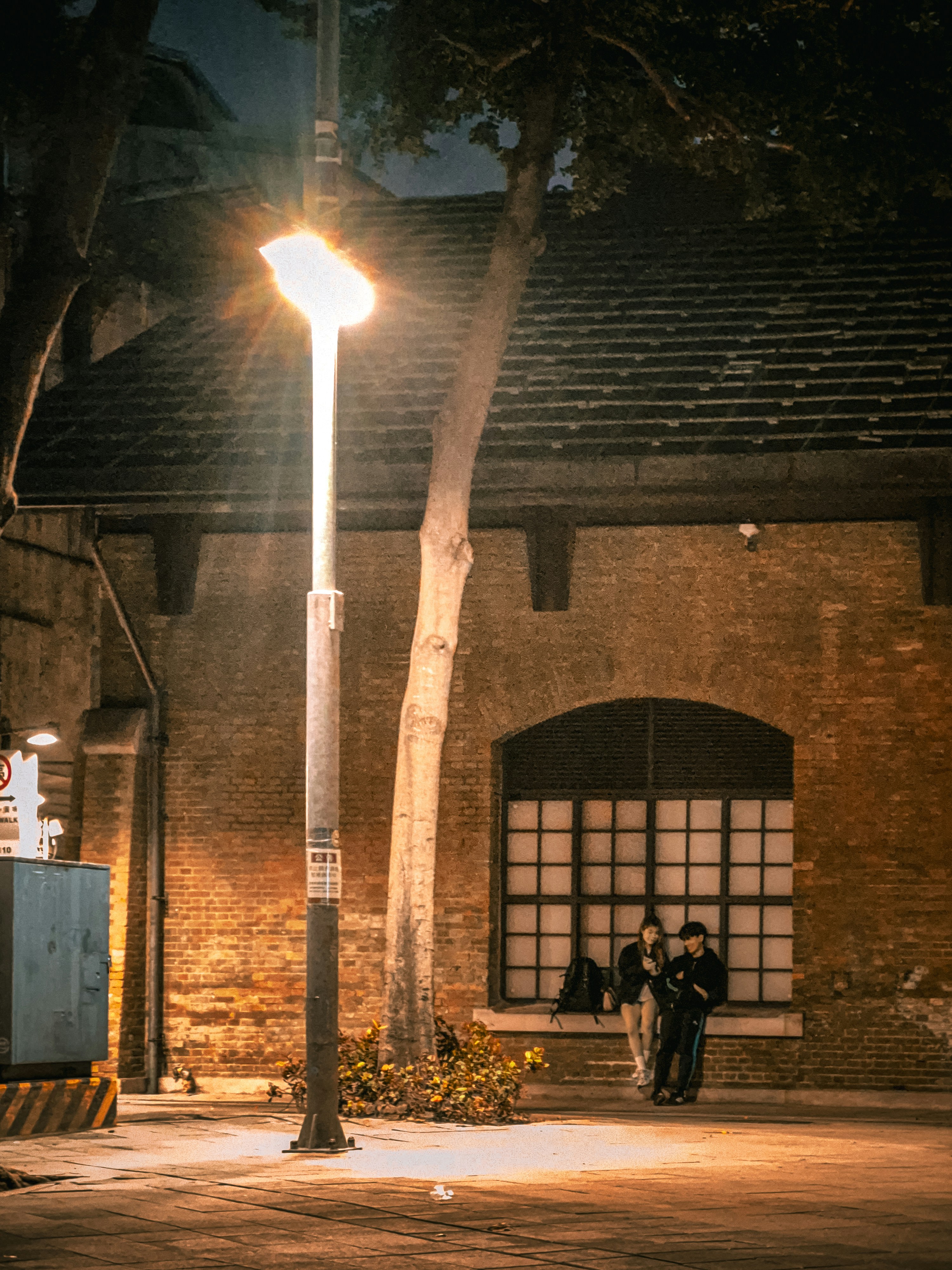 Night Street Bench: Couples Rest Under a Brick Facade