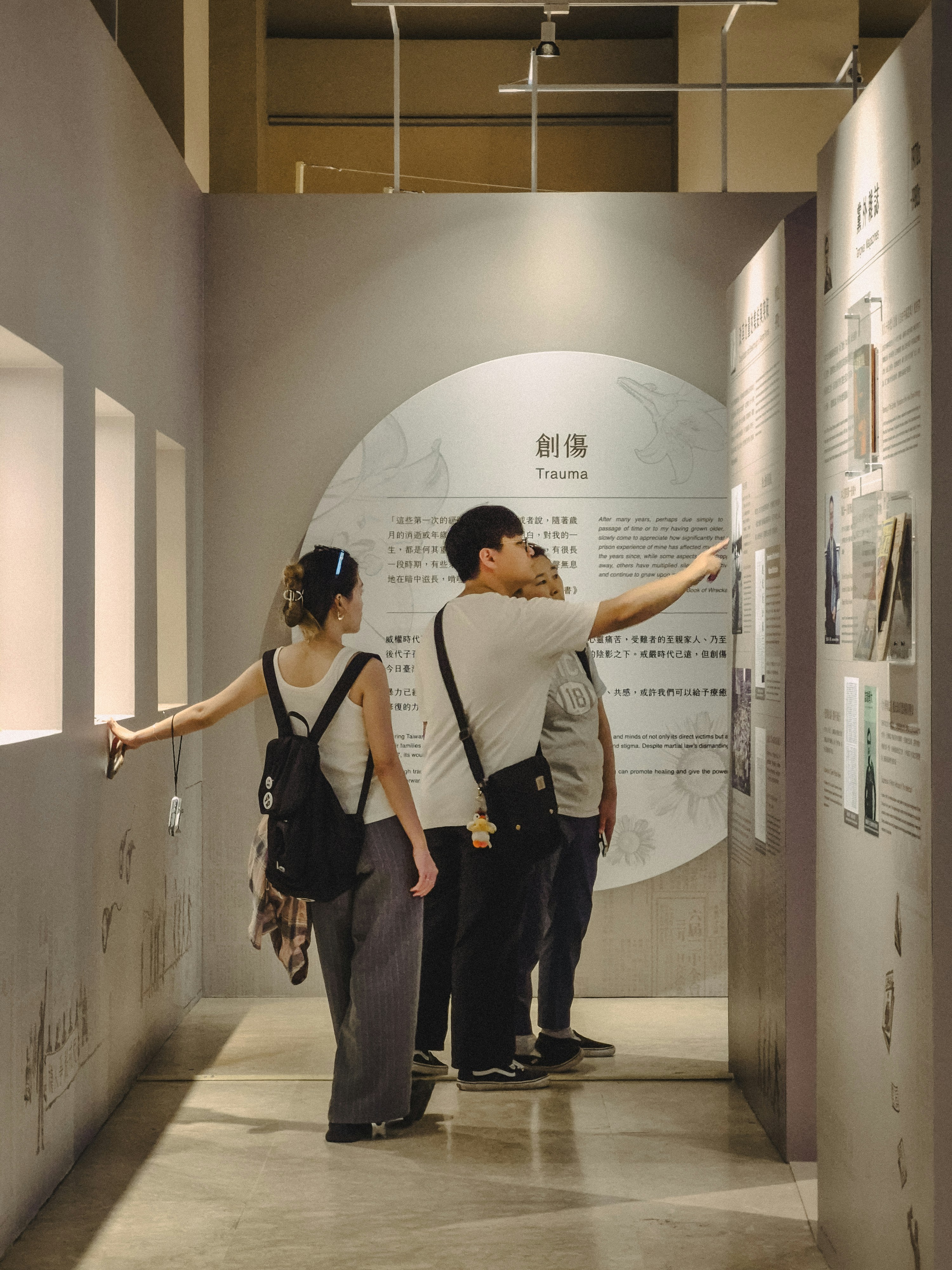 Museum Corridor Convergence: A duo of visitors explores a trauma exhibit