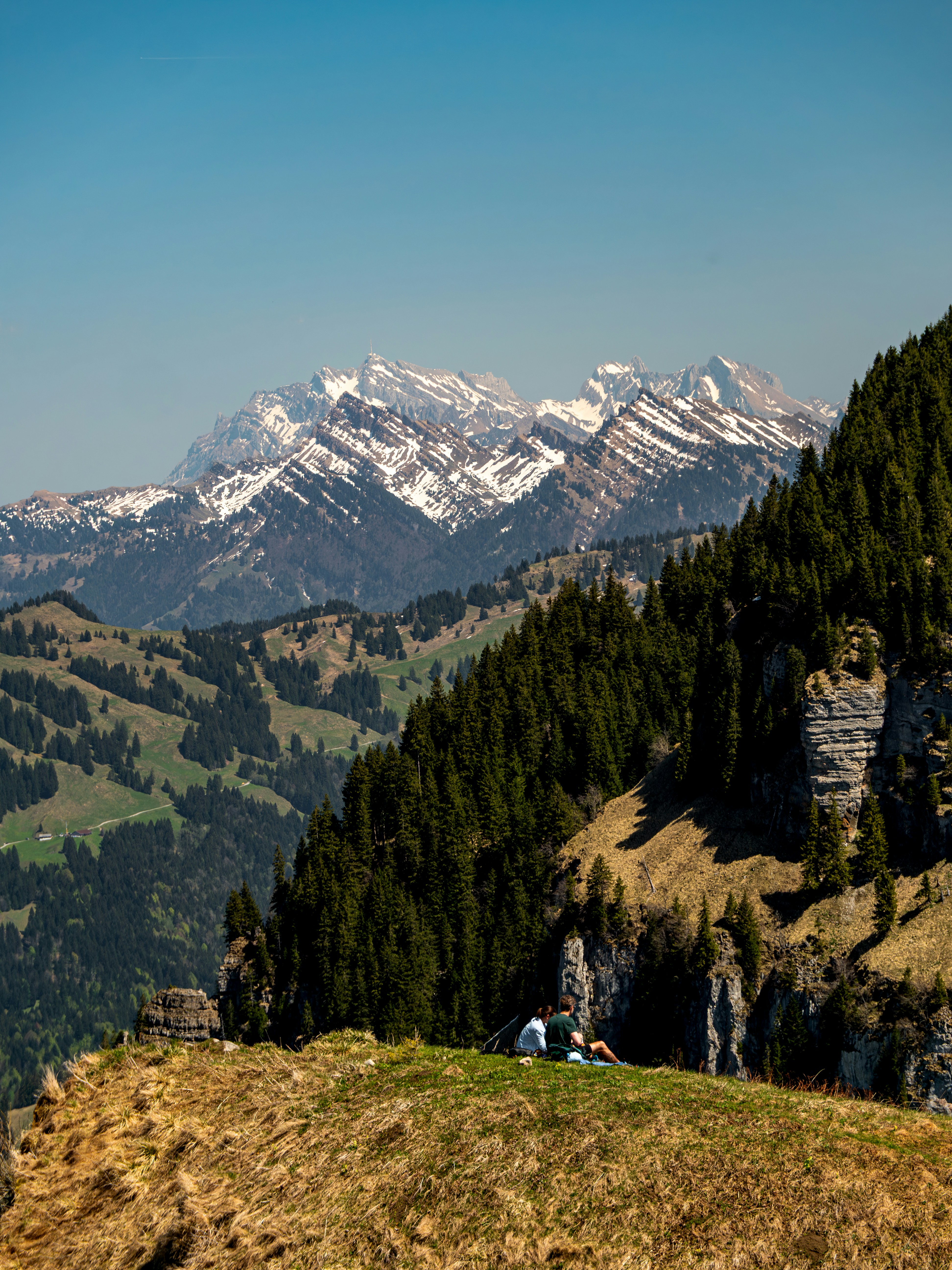 Hikers on a sunlit ridge with snow-dusted Alps beyond