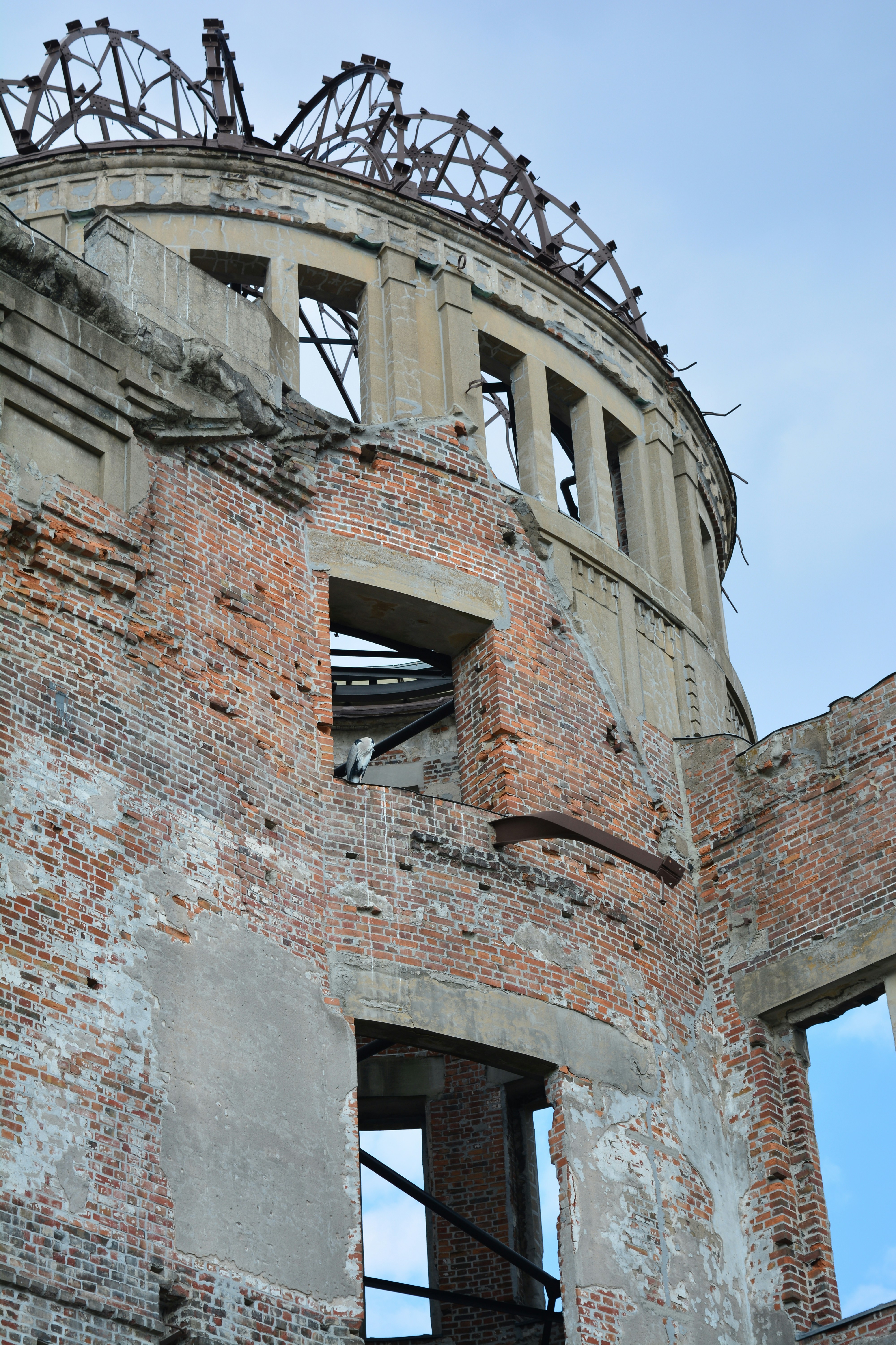 Ruined circular observatory rises with exposed brick and steel lattice against a pale blue sky