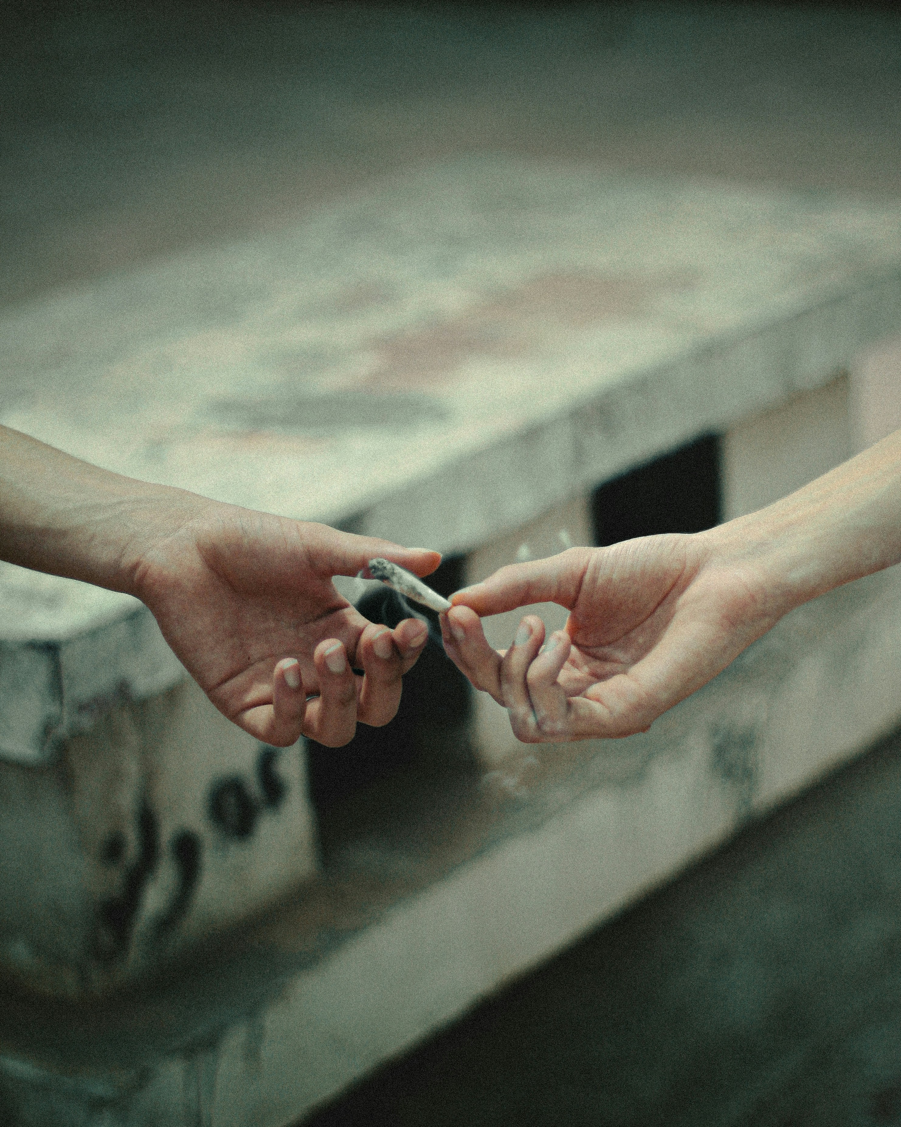 Hands Passing a Small Object Across a Concrete Edge