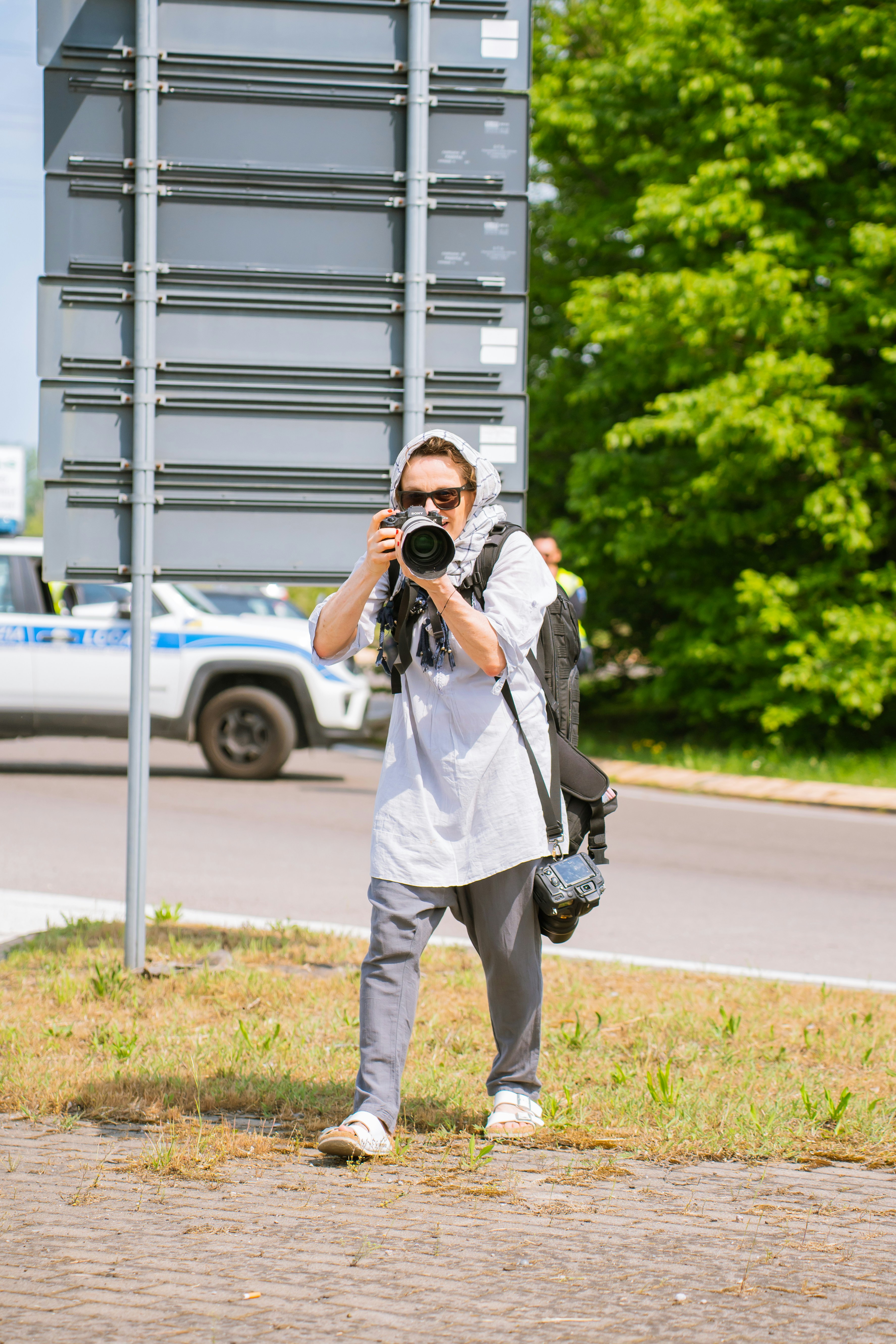 Street Photographer in a Light Hoodie Aiming the Canon at the City Edge