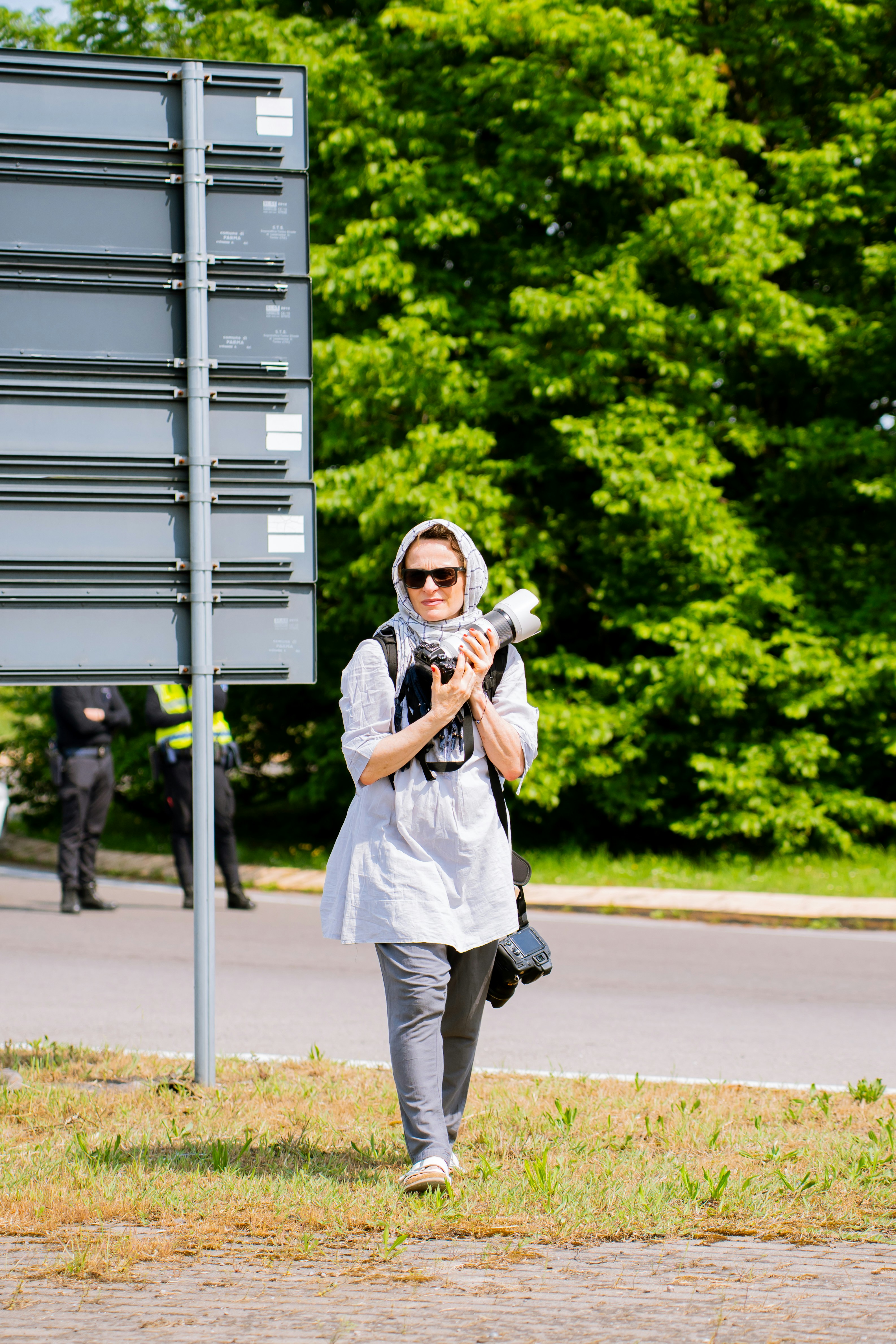 Photographer in a Light-Gray Tunic with Telephoto Lens in a Green Park