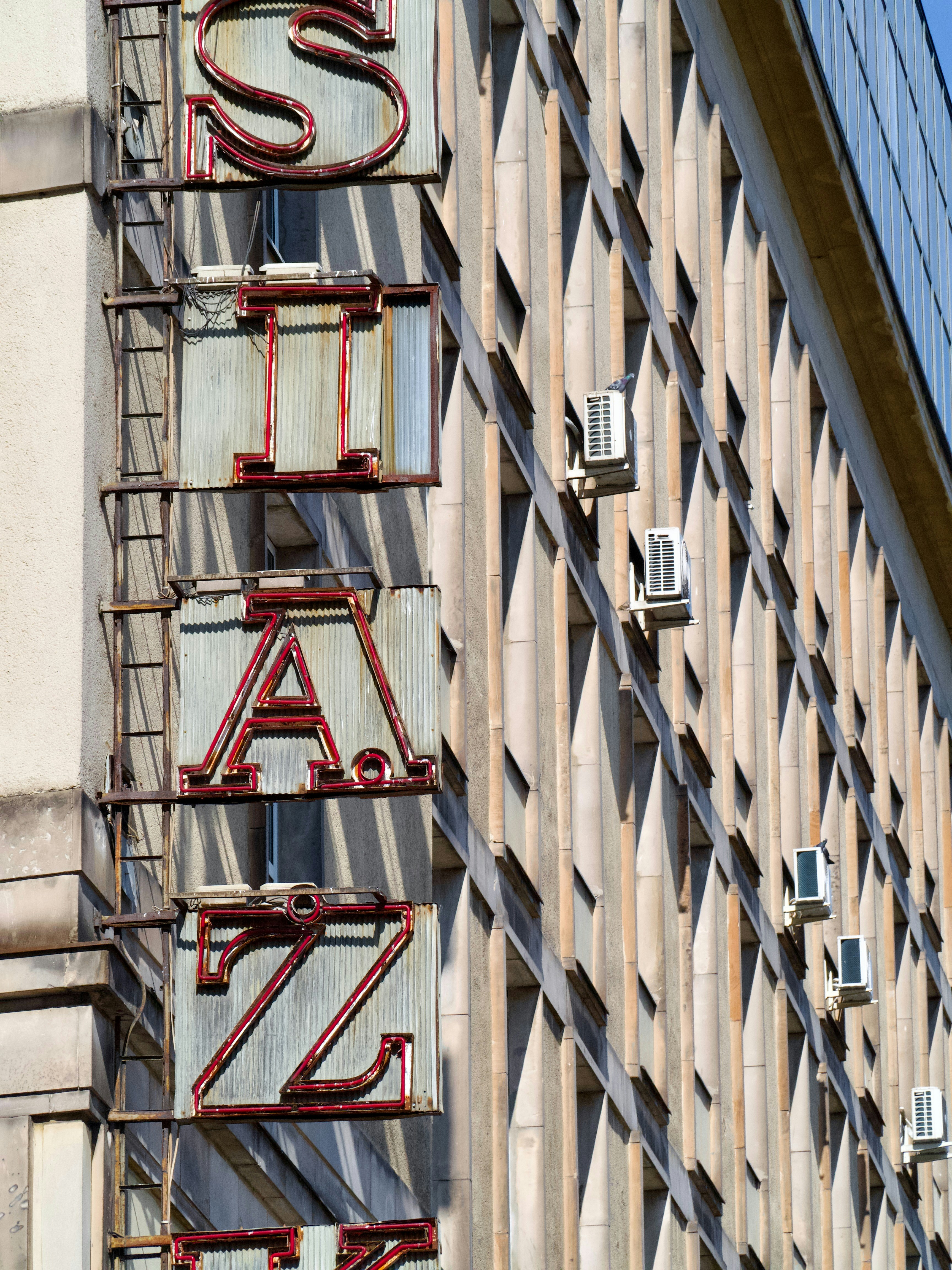 Neon Letters Climb a Facade: A Vertical Sign Spell of the City