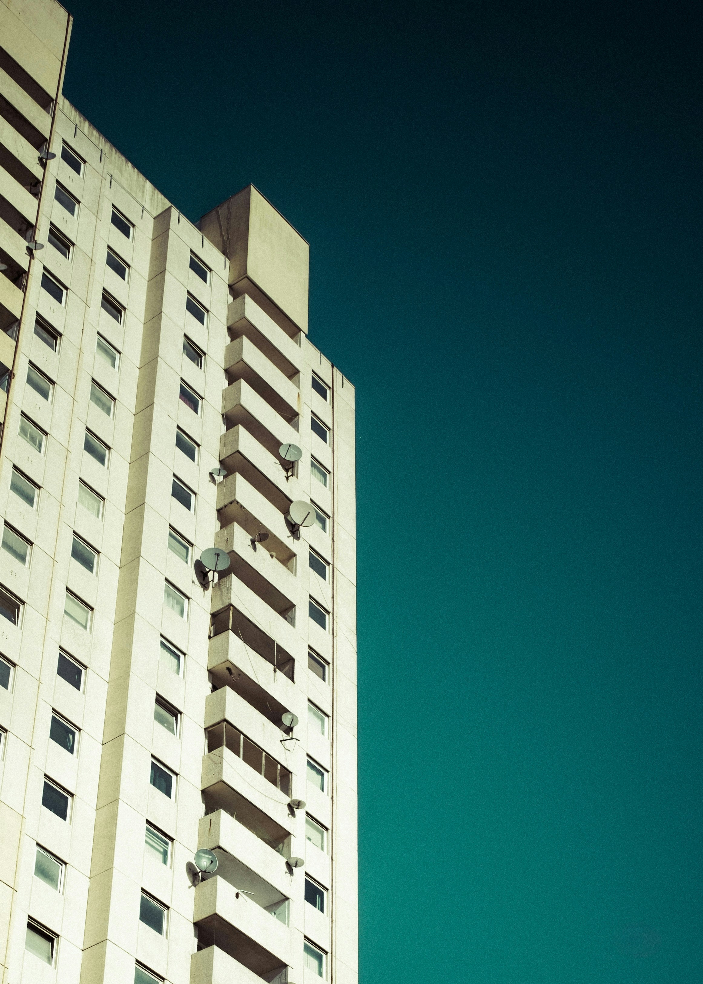 Urban Facade: Concrete Balcony Choir against a Deep Cyan Sky