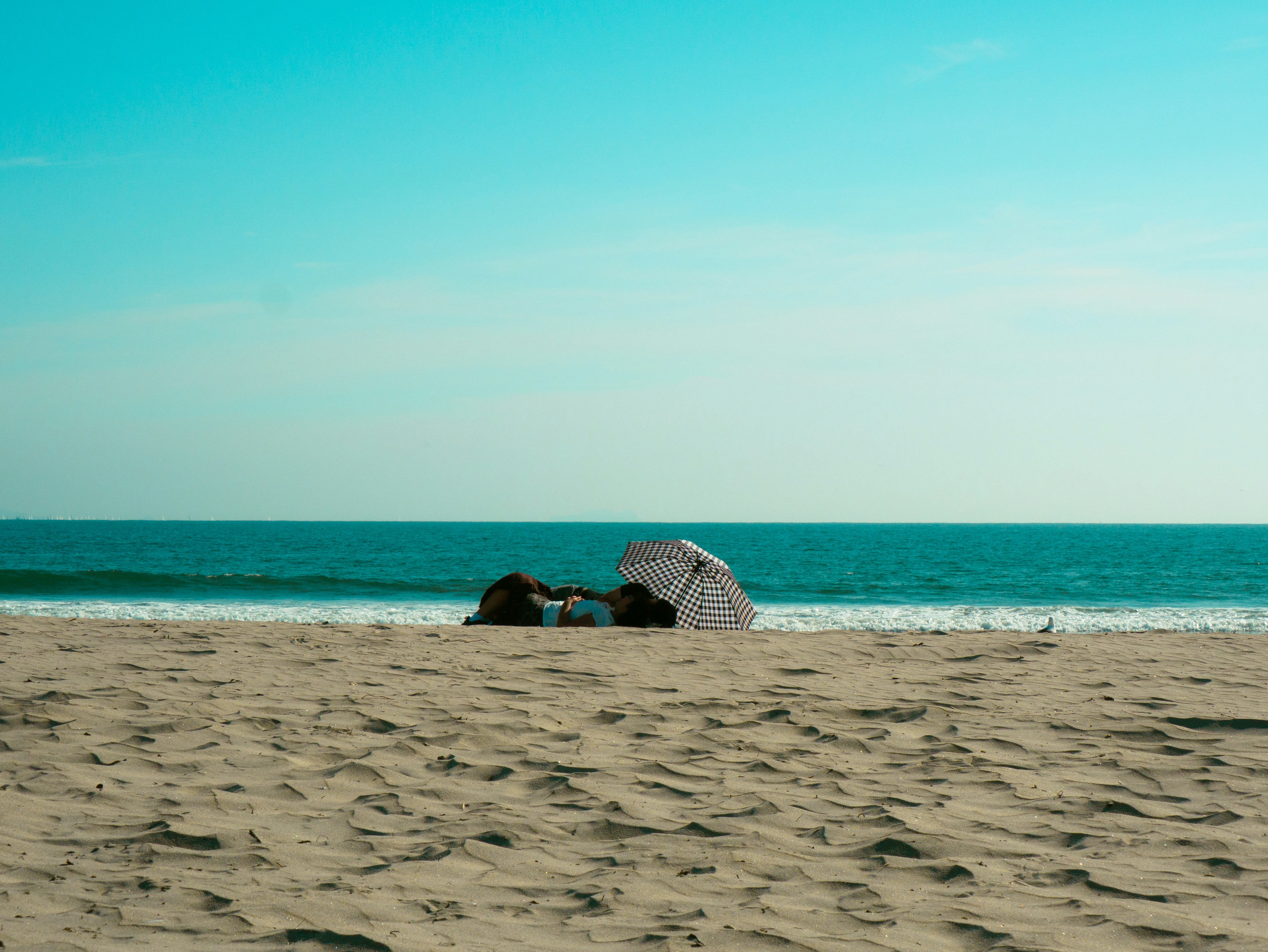 Beachside Respite: A Surreal Umbrella and Hidden Figures at Dune's Edge
