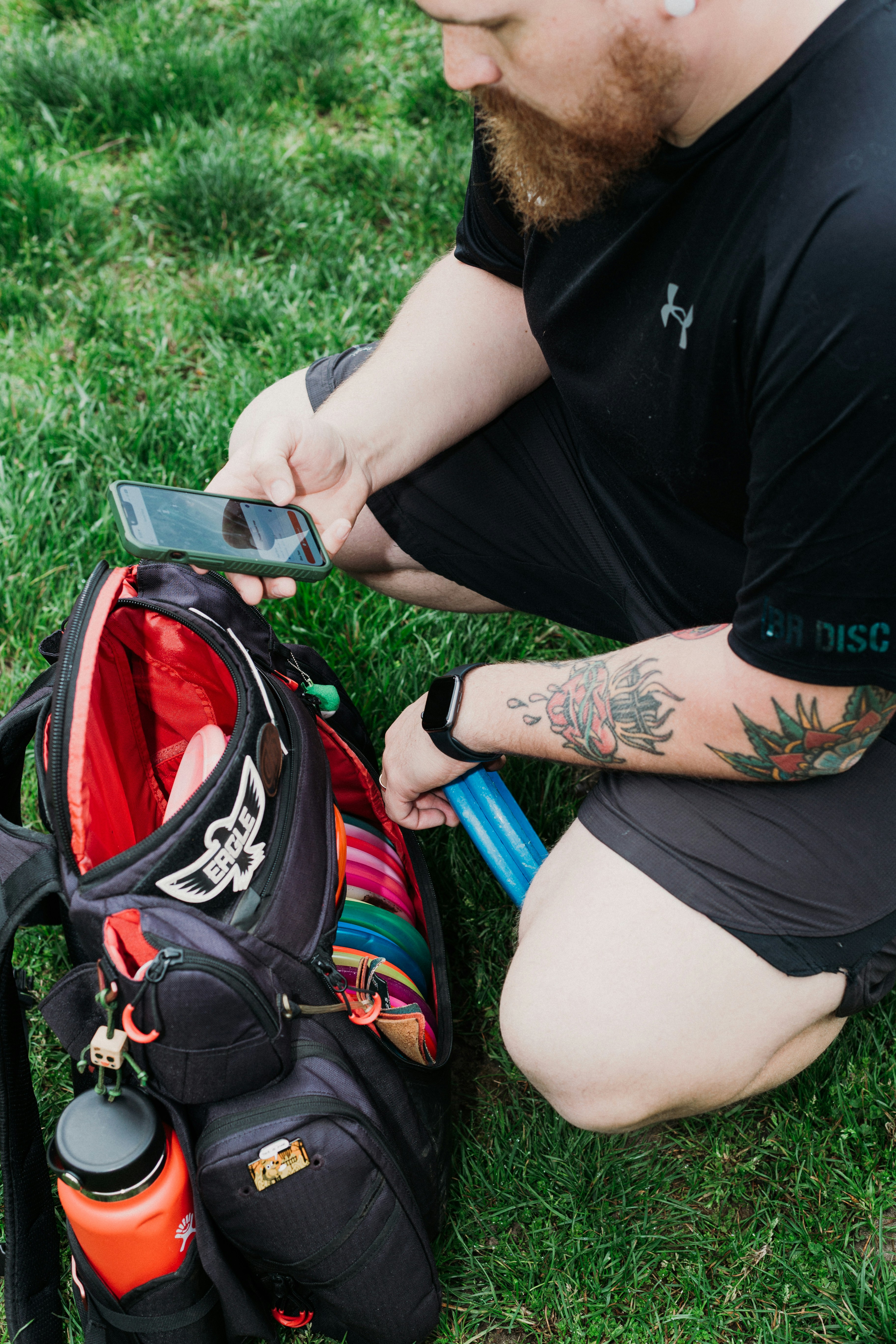 Field Pocket: A Bearded Player Scans a Disc Golf Backpack for Essentials