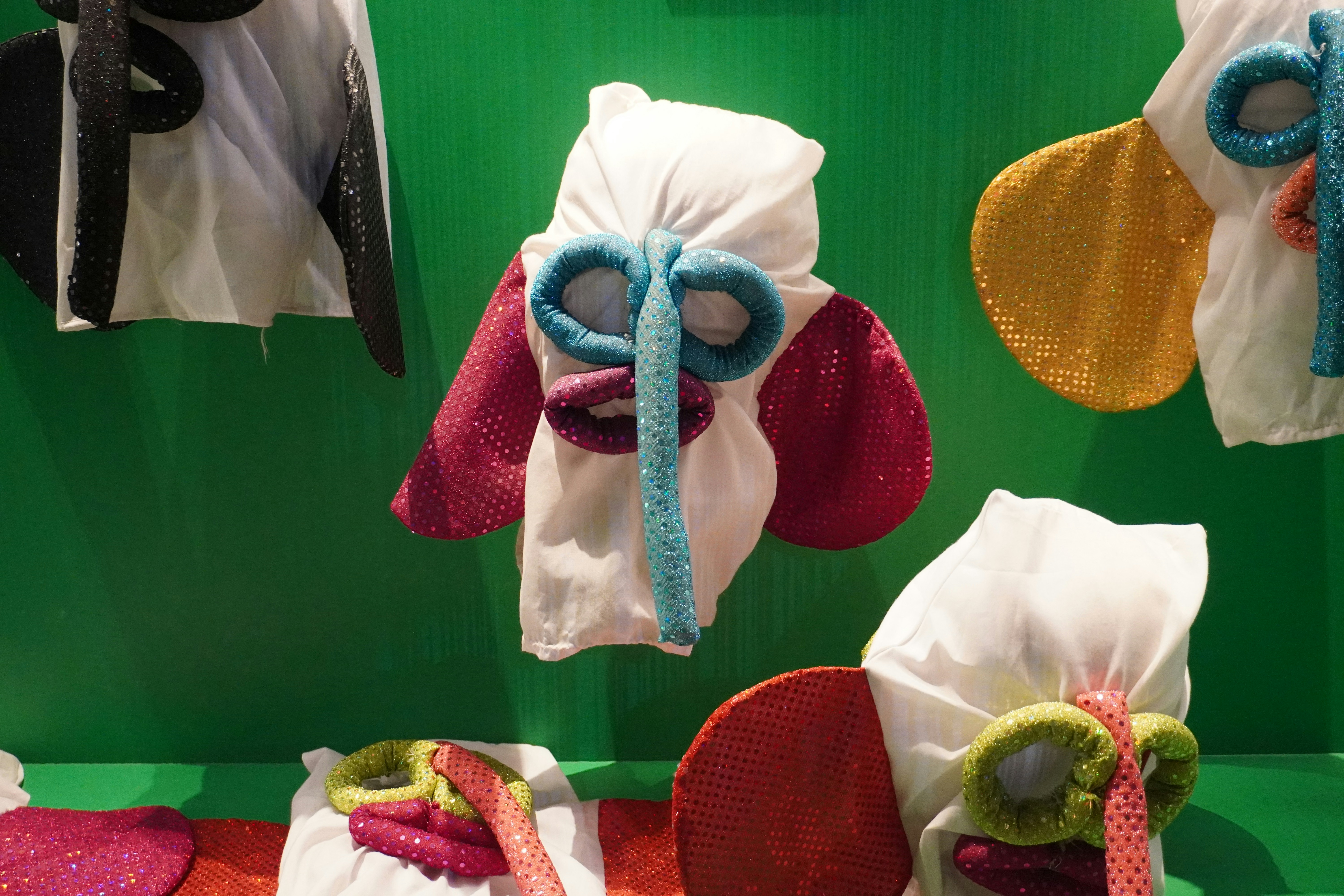 Colorful Mummified Ribbons: Plush Masks on a Green Stage