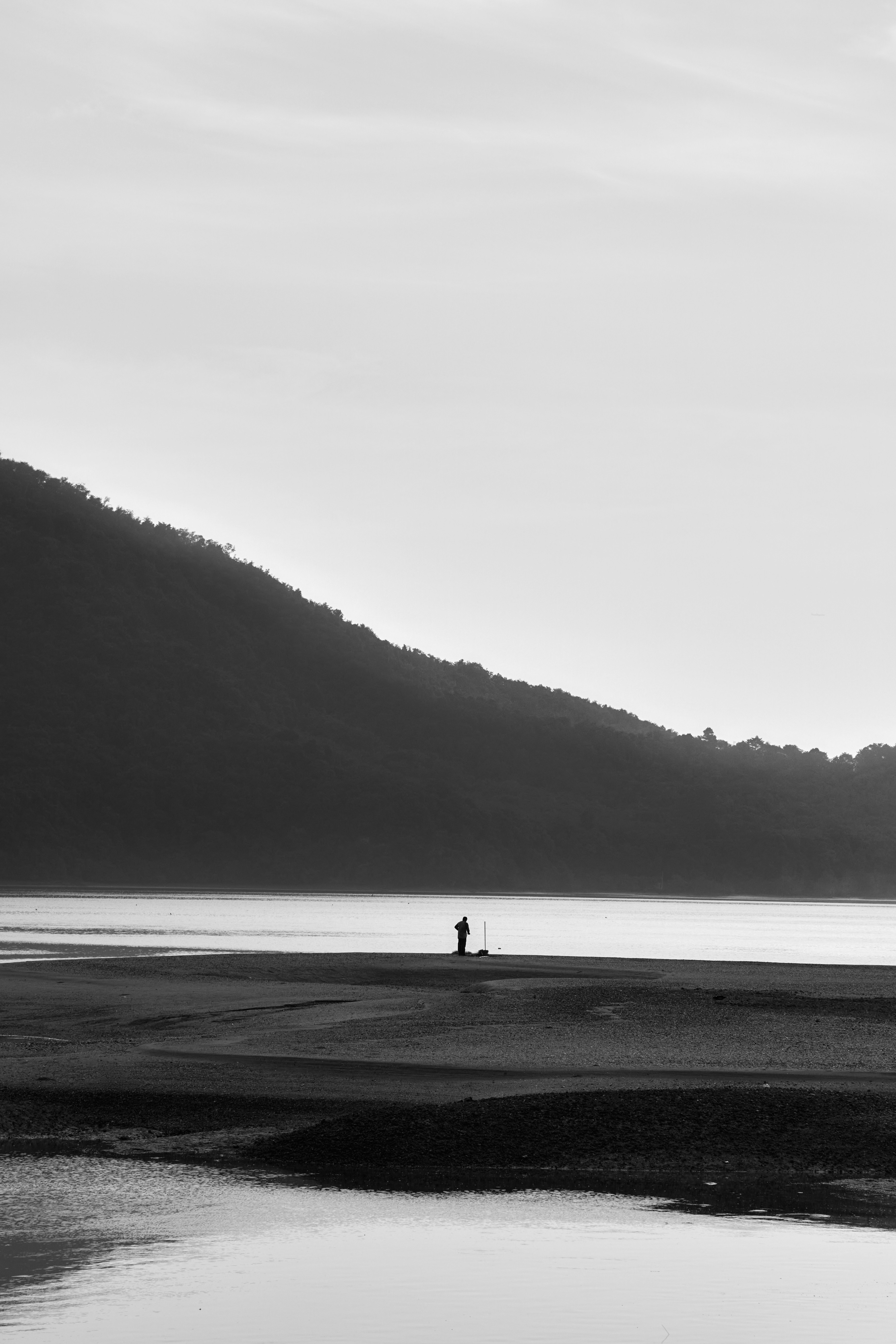 Silhouette on the Shore: A Lone Angler at Dusk
