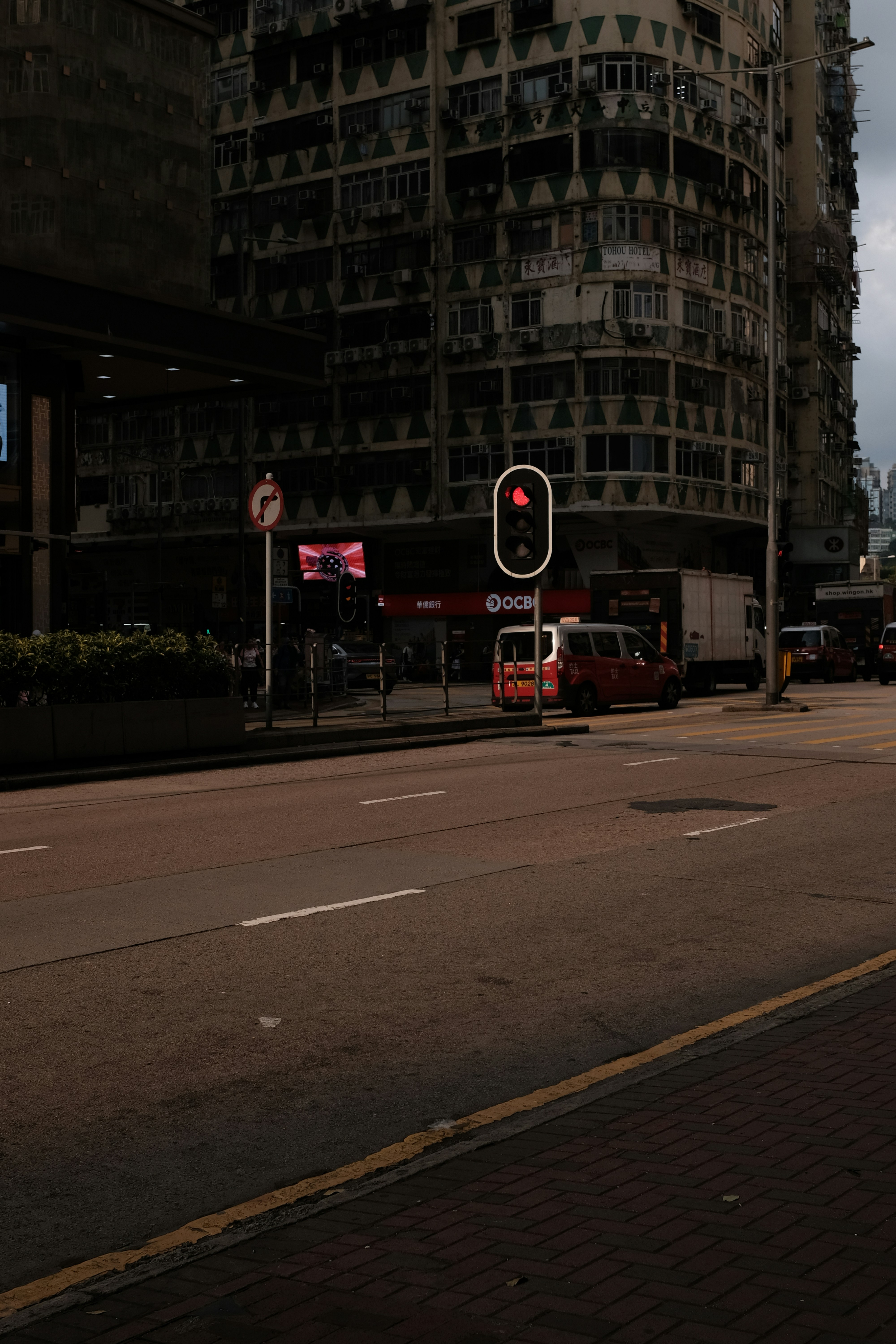 Red Taxi at a Quiet Crossing Under a Weathered High-Rrise