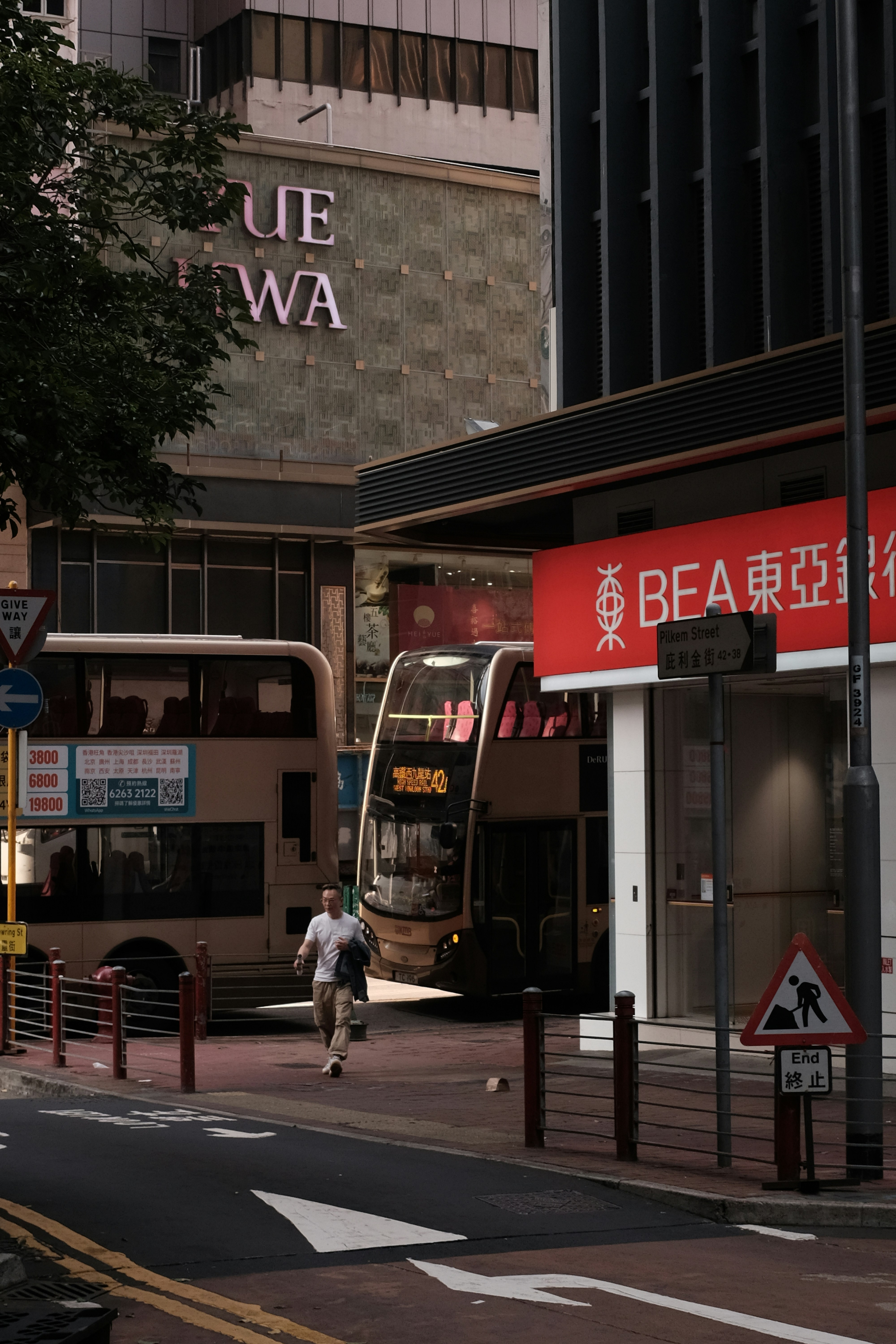 Urban Crossing: A Pedestrian Emerges Between Bus and Bank
