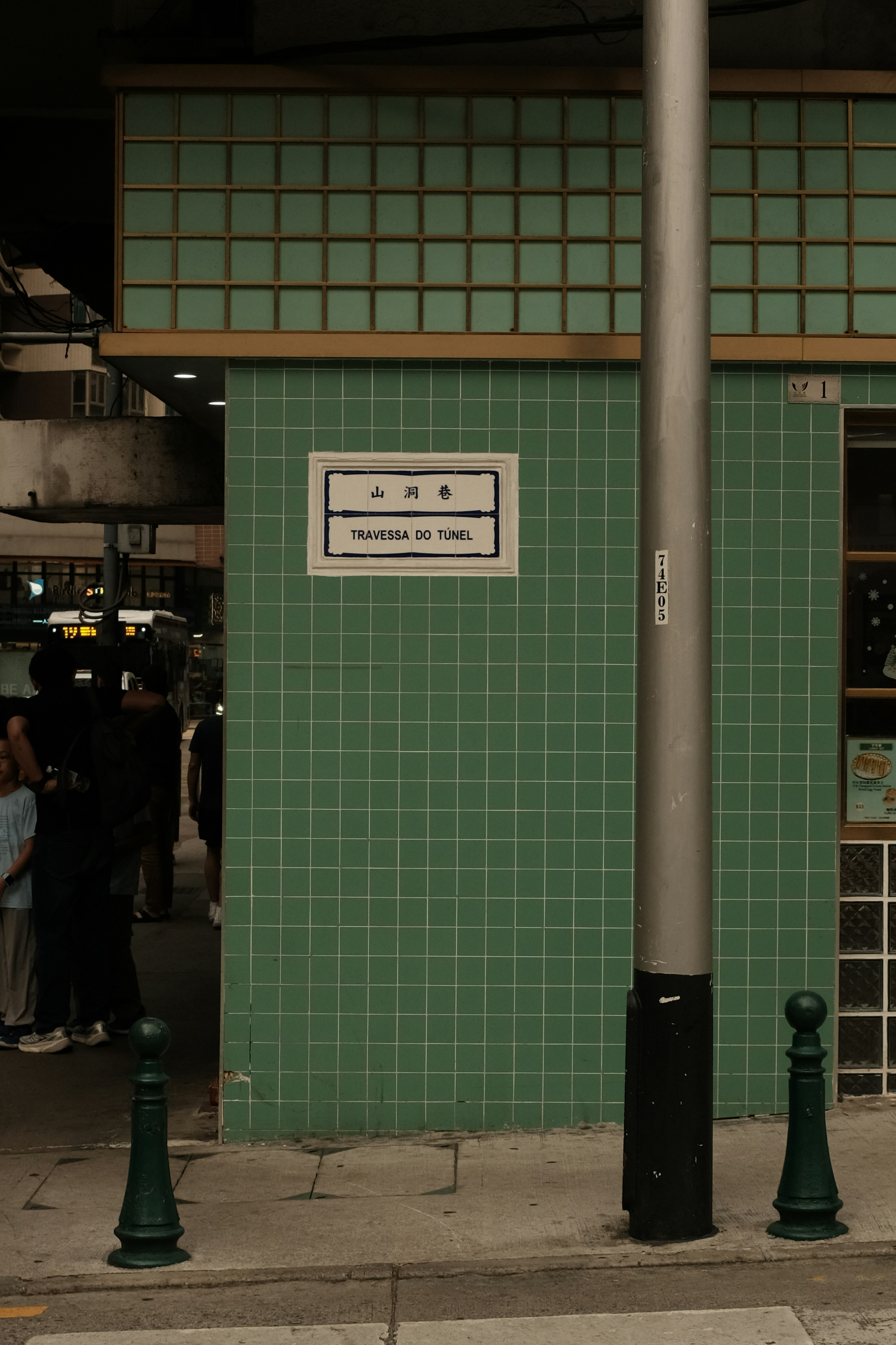 Green-Tiled Tunnel Sign Behind a Pedestrian-Filled Street