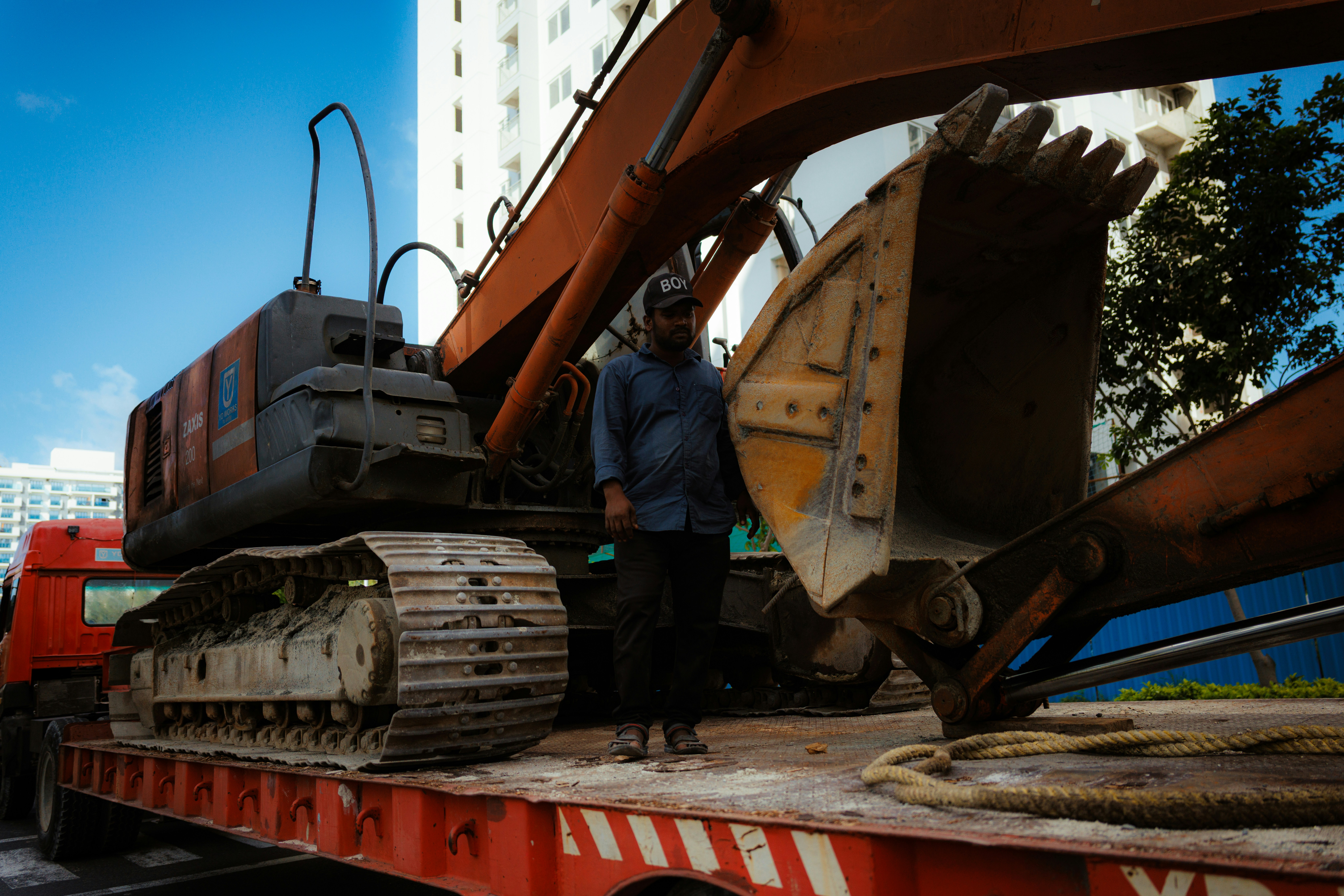 Construction Giant on a Red Platform: Man Beneath the Excavator Arm