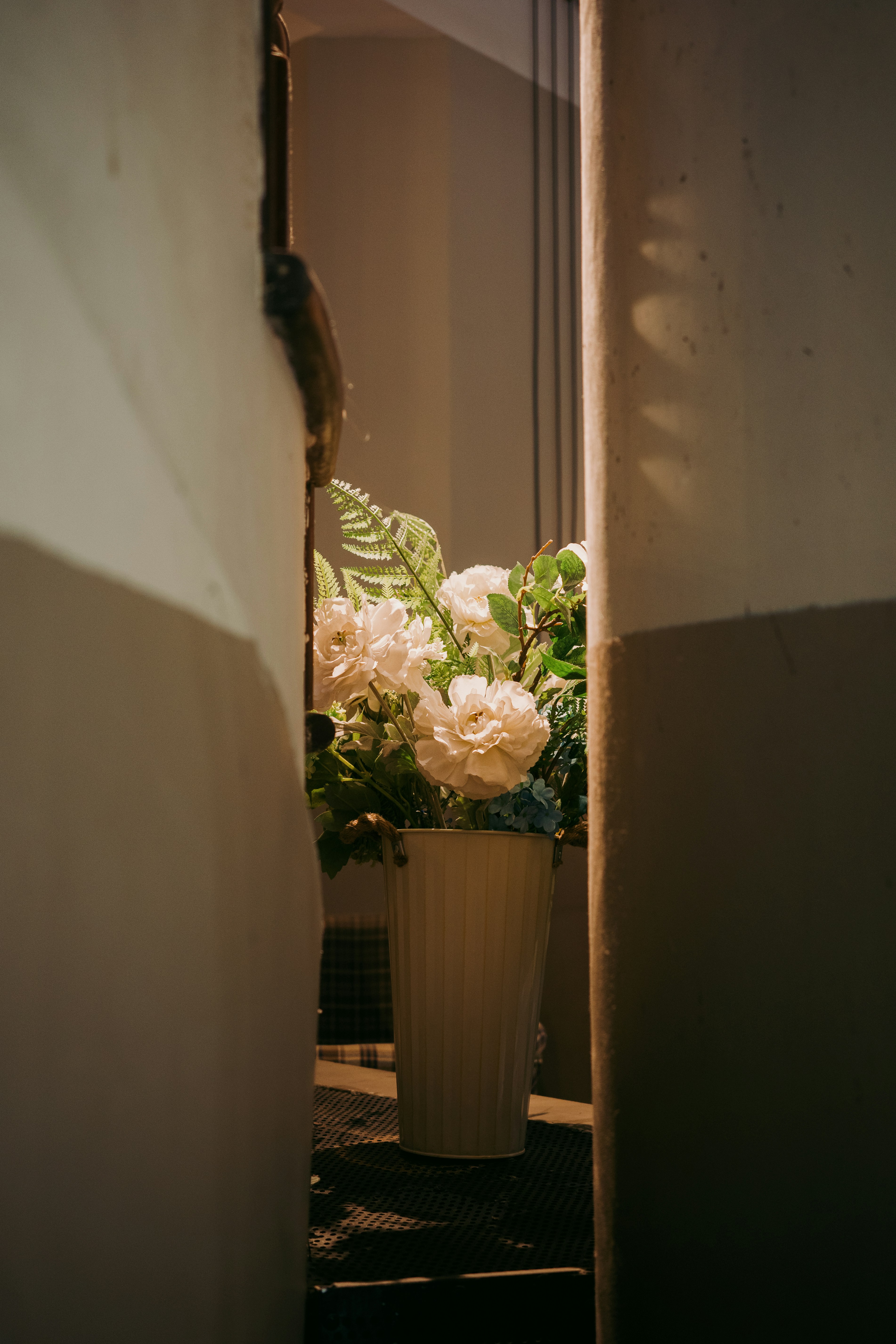 Vase of white blooms framed by narrow doorway shadows