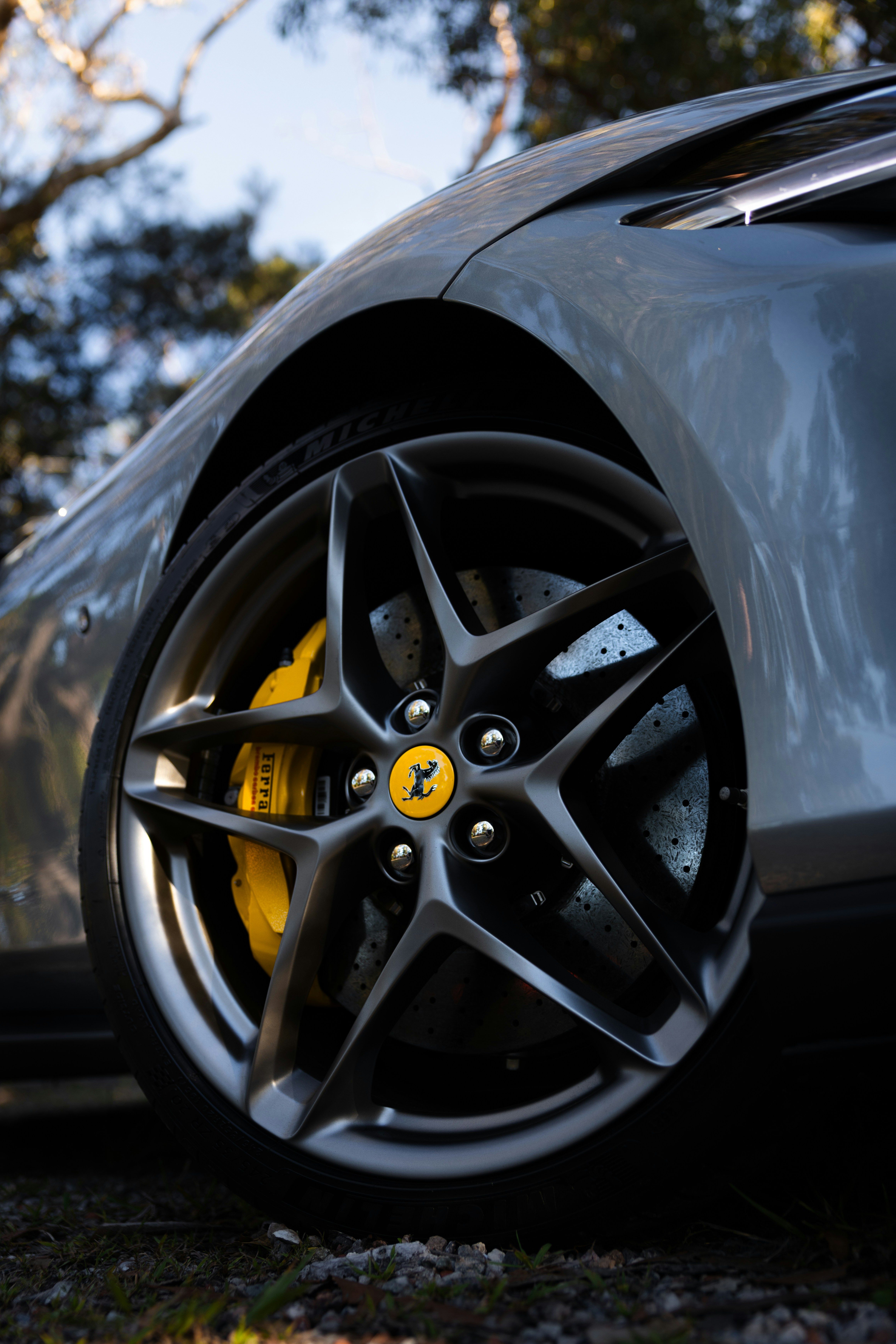 Ferrari-branded brake details: close-up of a silver hypercar wheel with yellow calipers