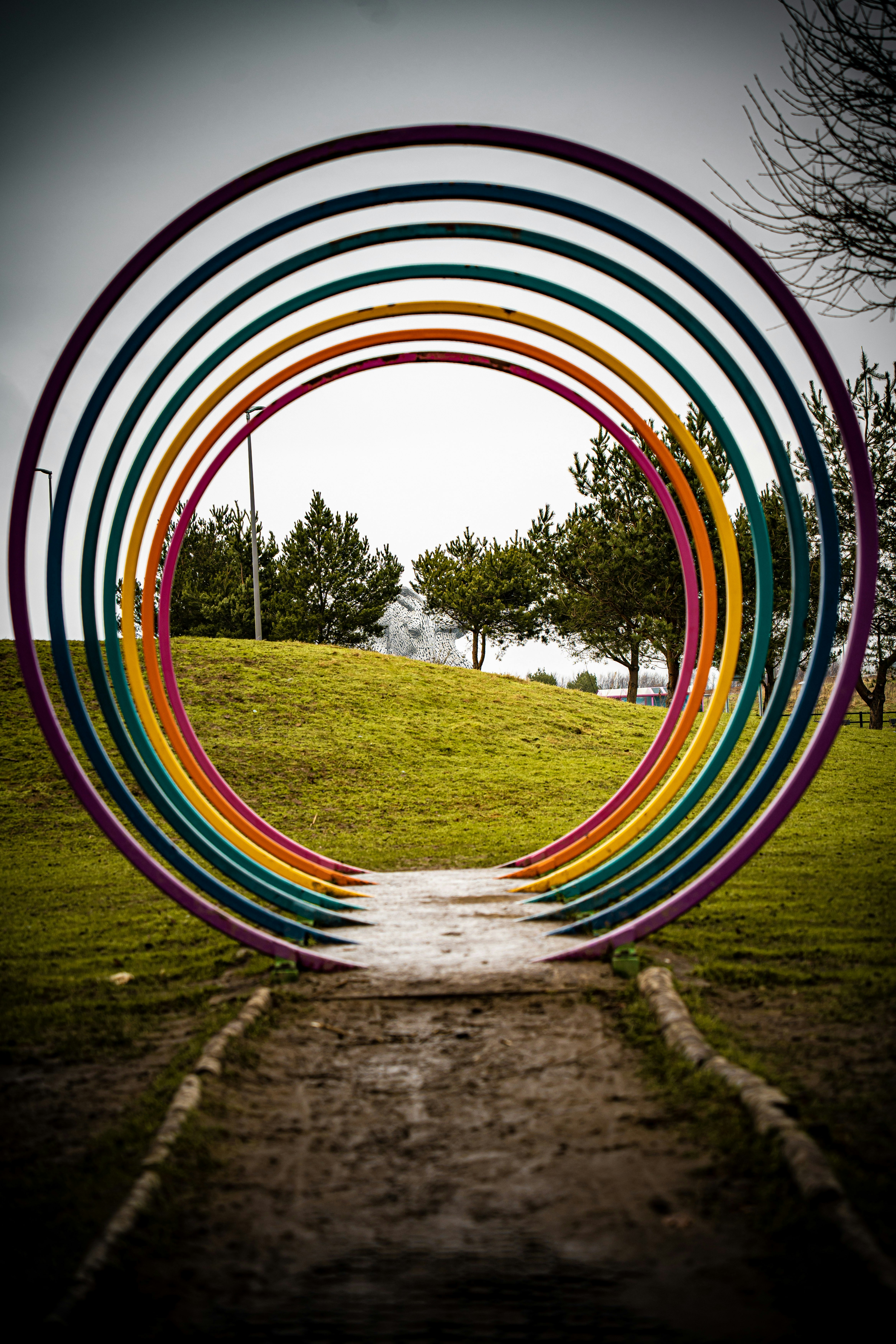 Circular Arc: A Rainbow Tunnel framing a grassy park under a cloudy sky