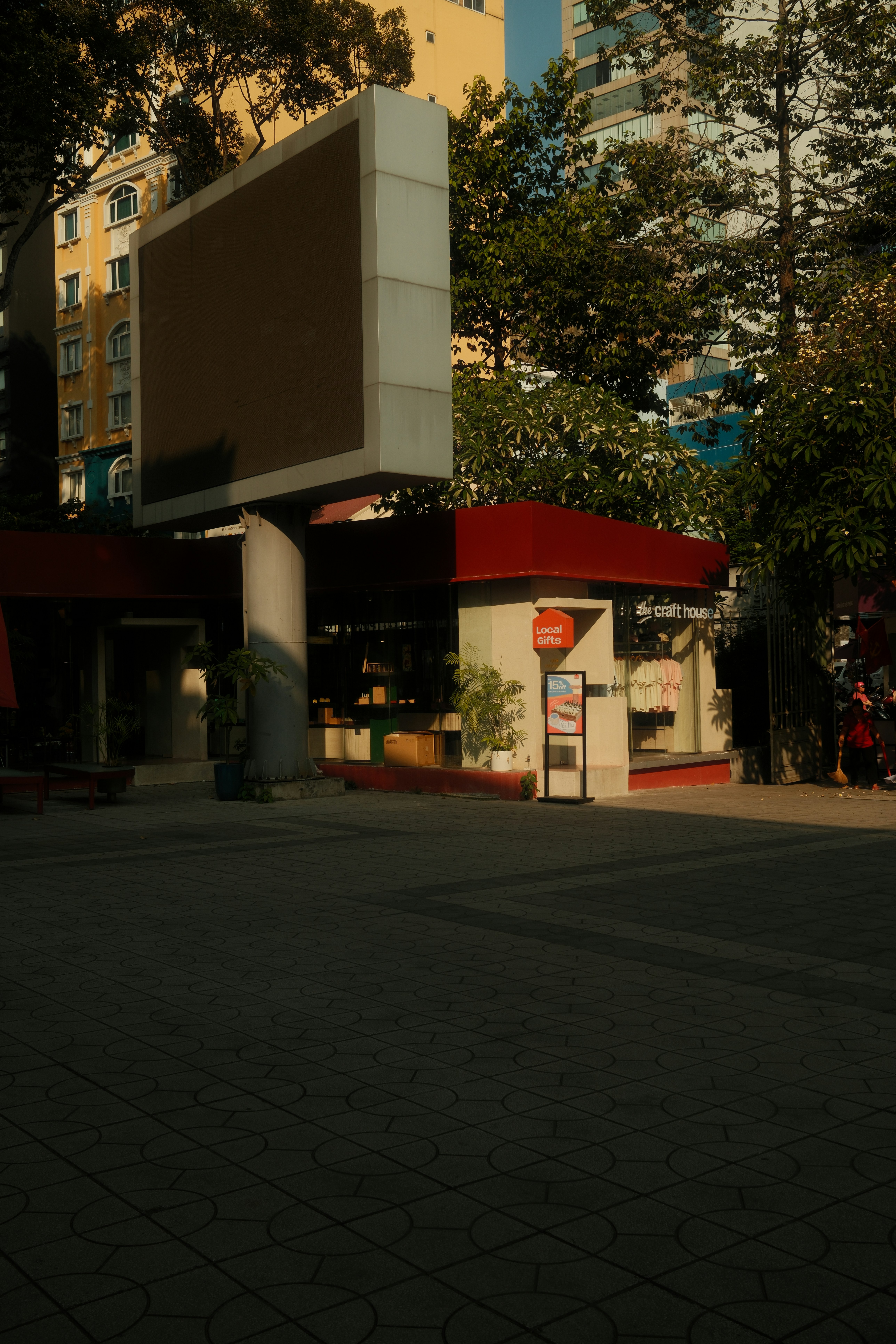 Urban Canopy: A Red-Trim Corner Shop Beneath Shading Trees