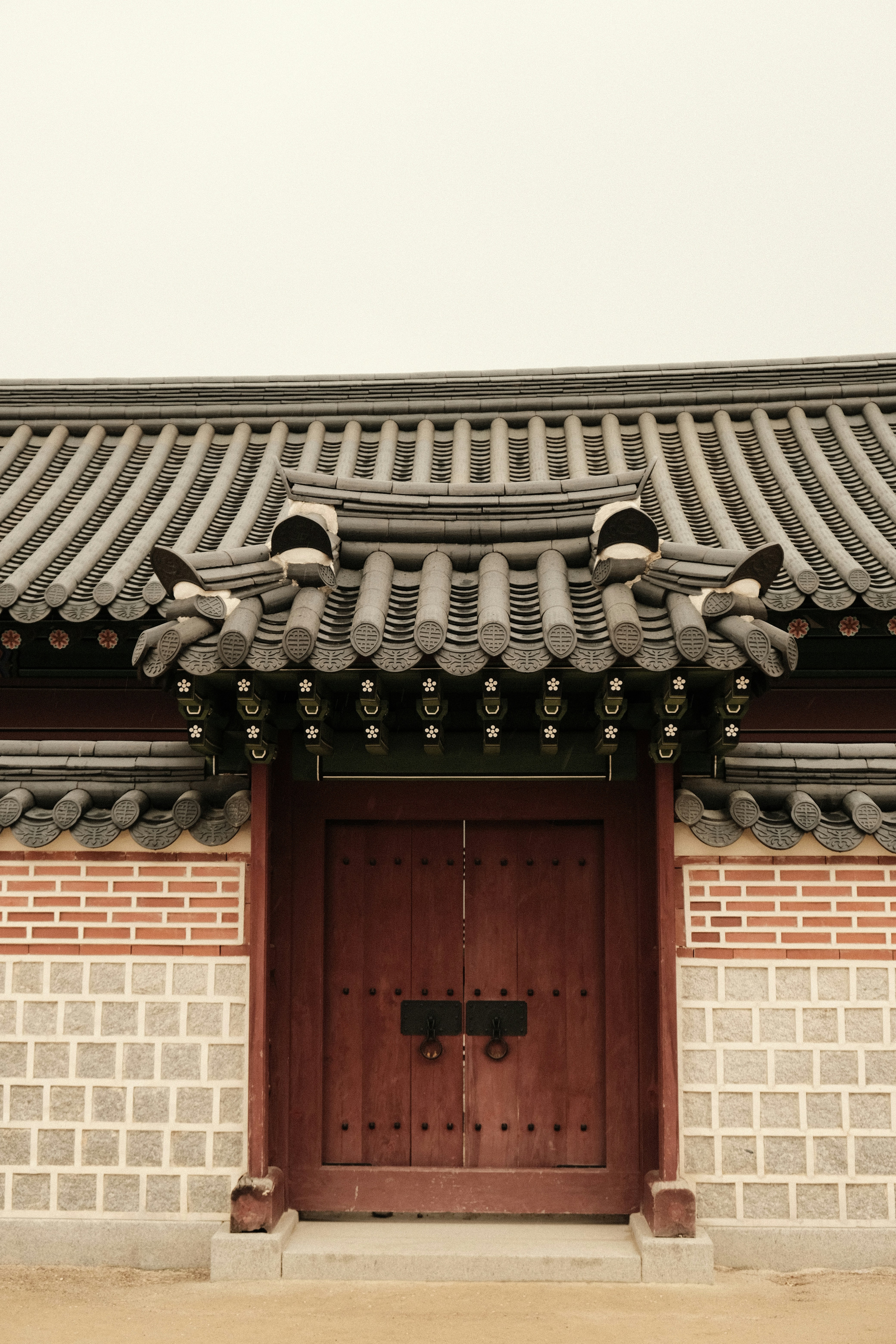 Red Wooden Doorway Framed by Carved Timber Roof of a Hanok