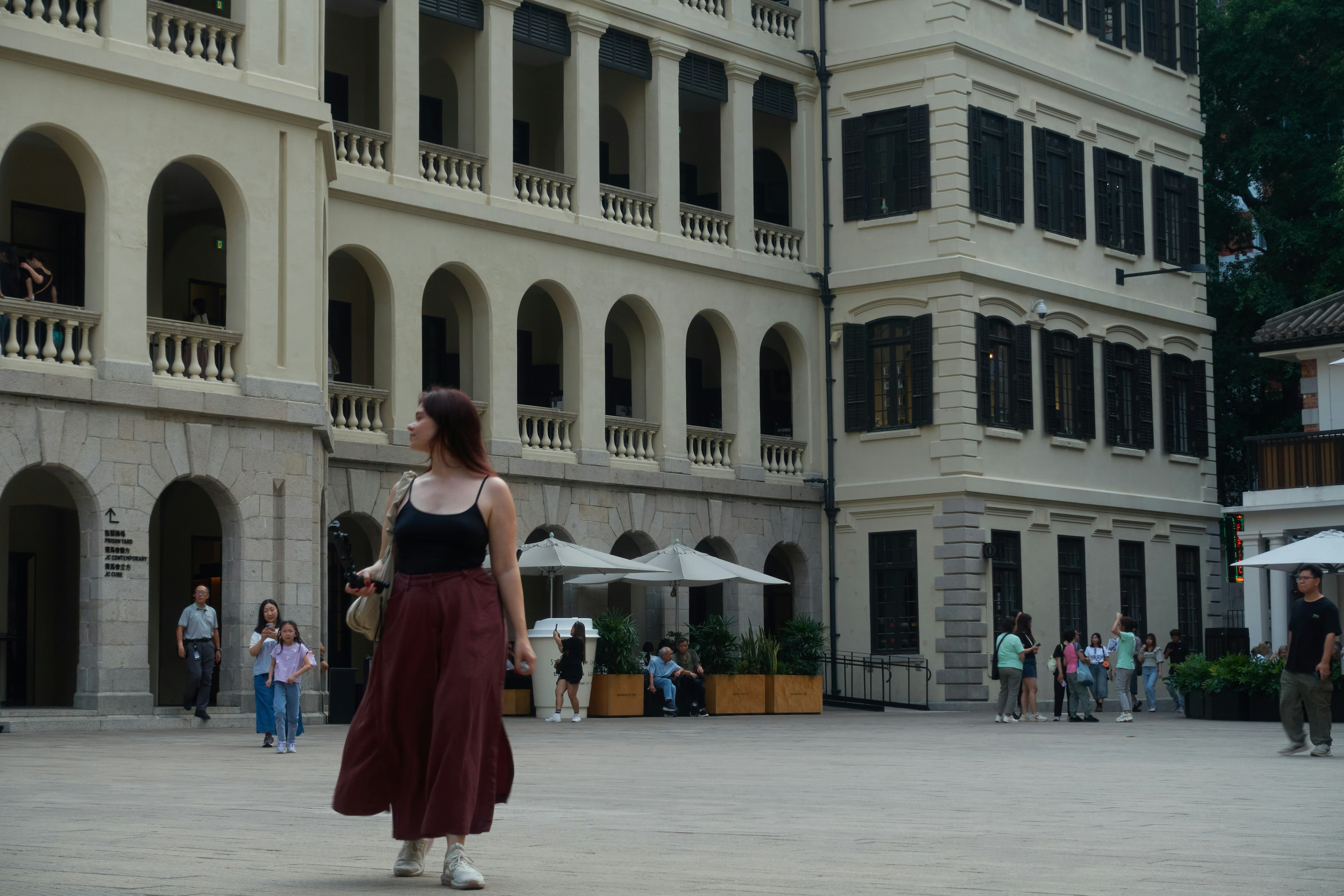 A lone observer walks the plaza beneath arched façades