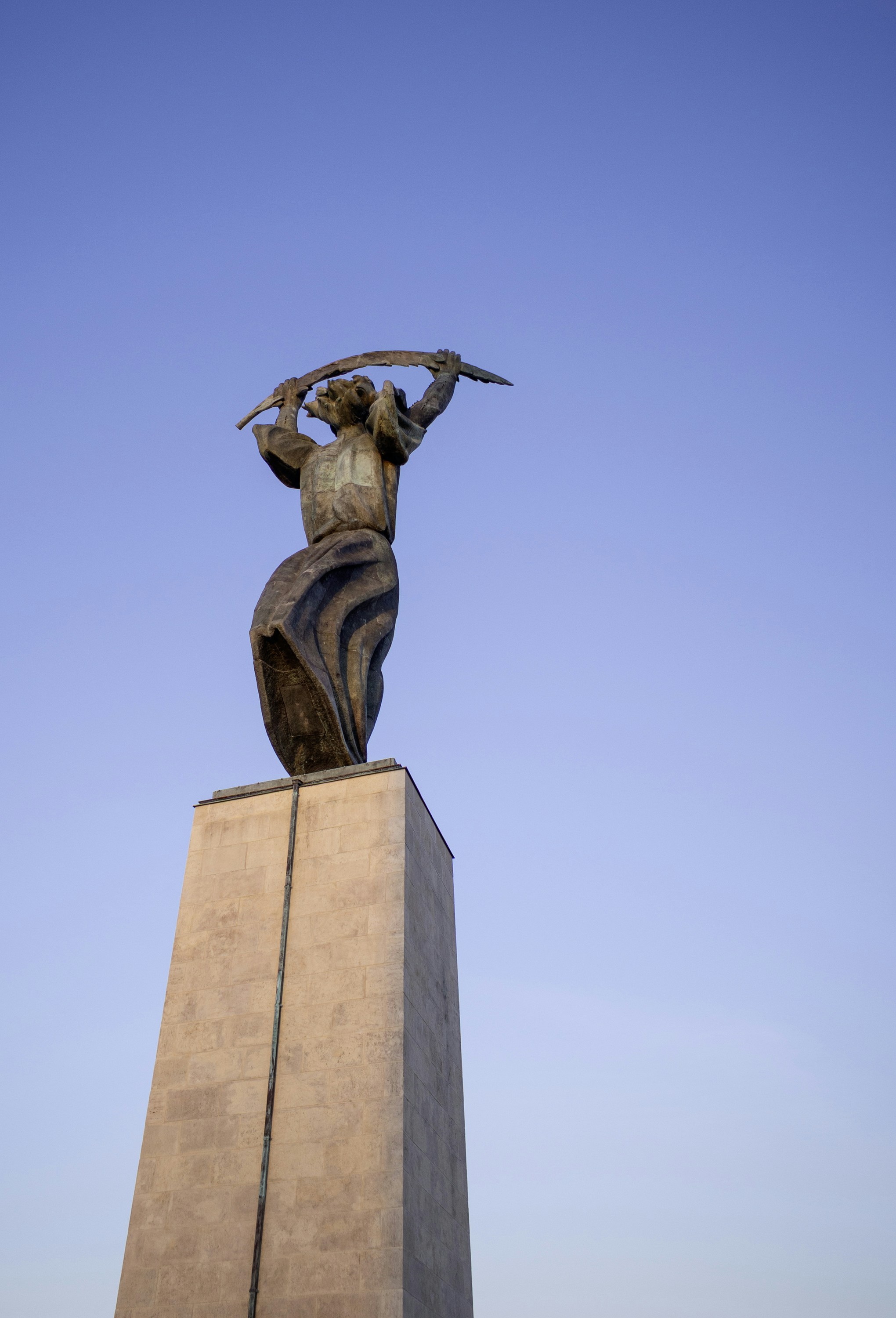 Sculpted Sentinel: A Dawn-Streaked Statue Reaching Toward the Sky