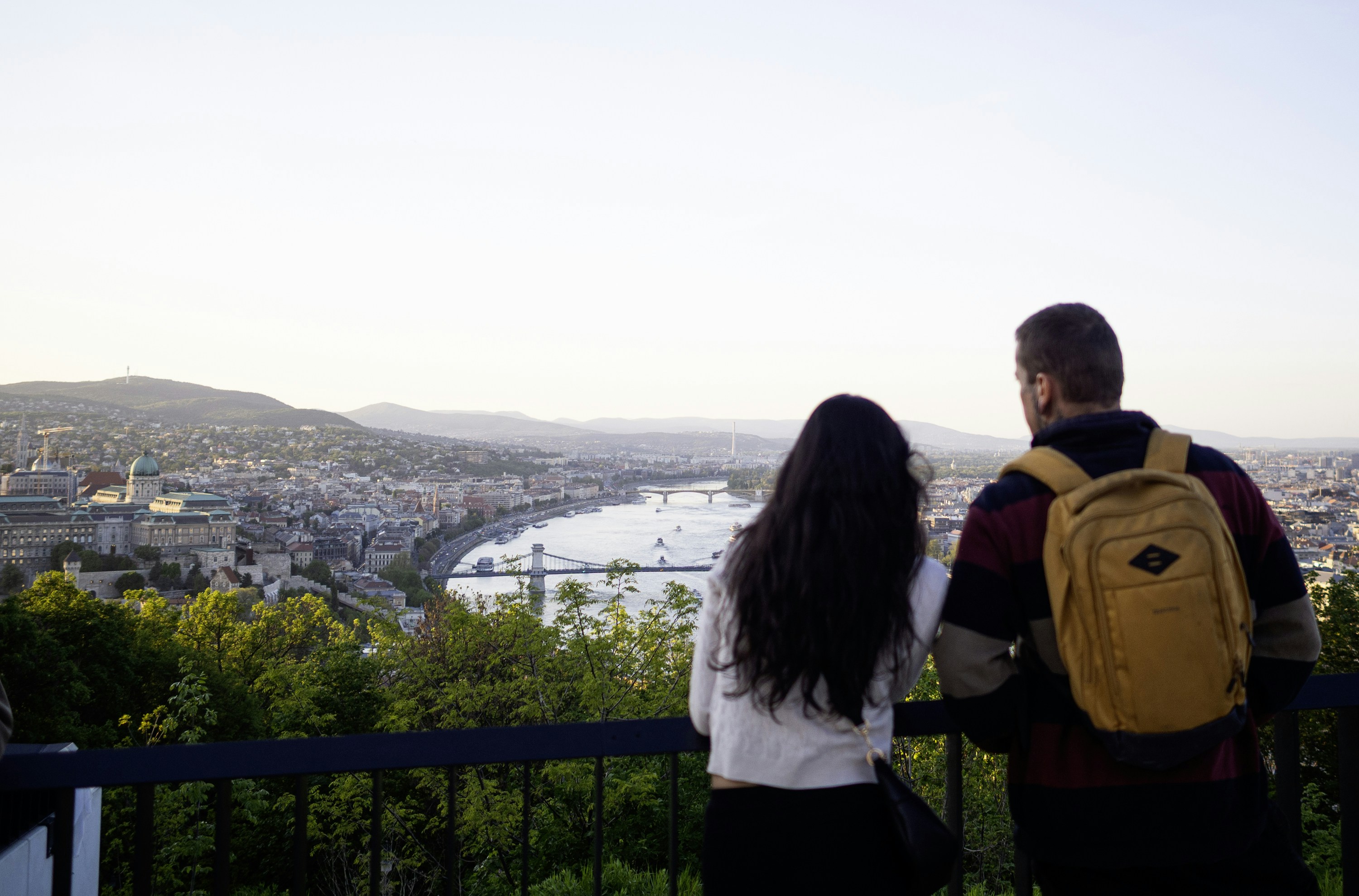 Two Travelers Overlook a City Span Beneath an Expansive Sky