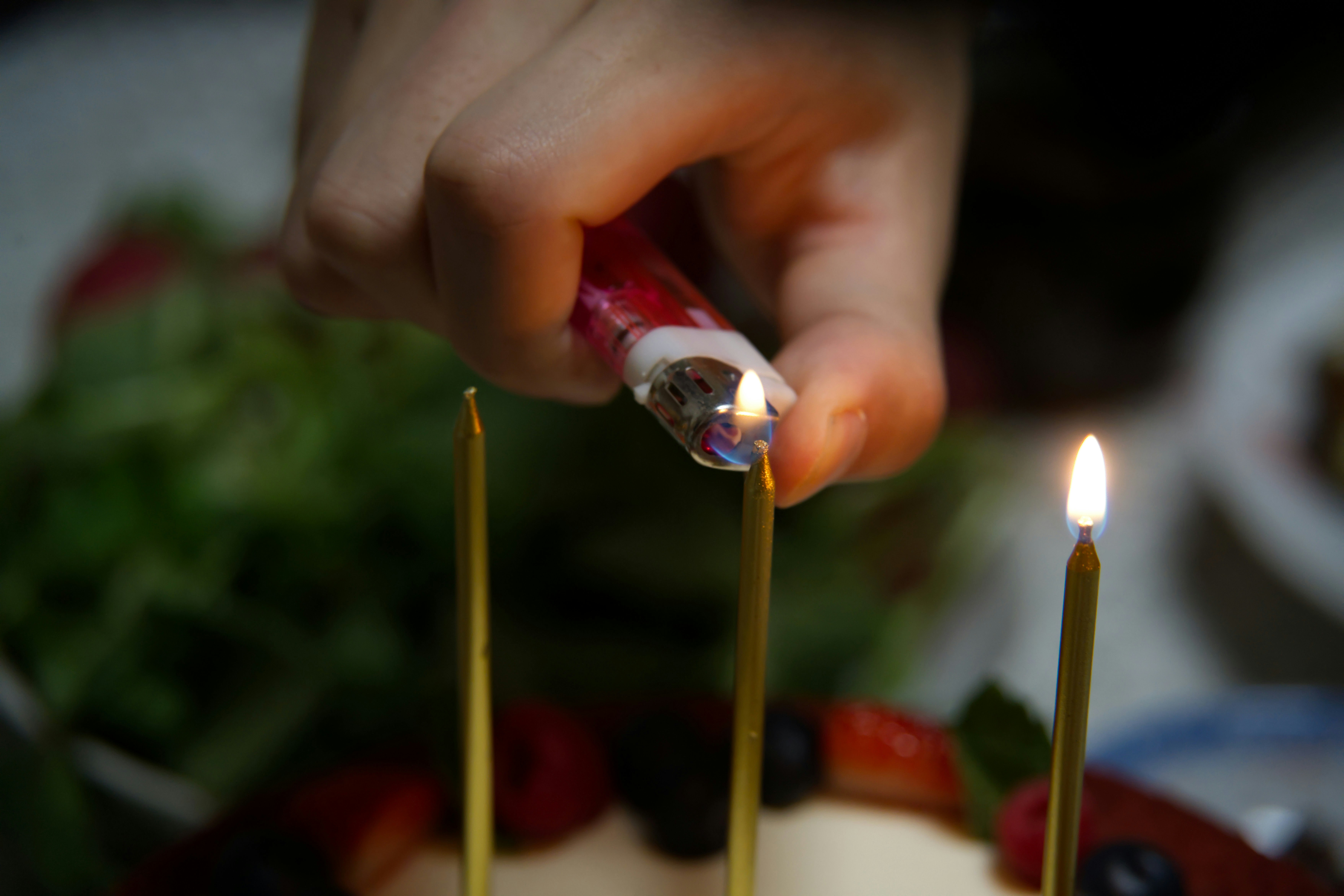 Flame-guided ritual: hands, candle, and cake in soft focus