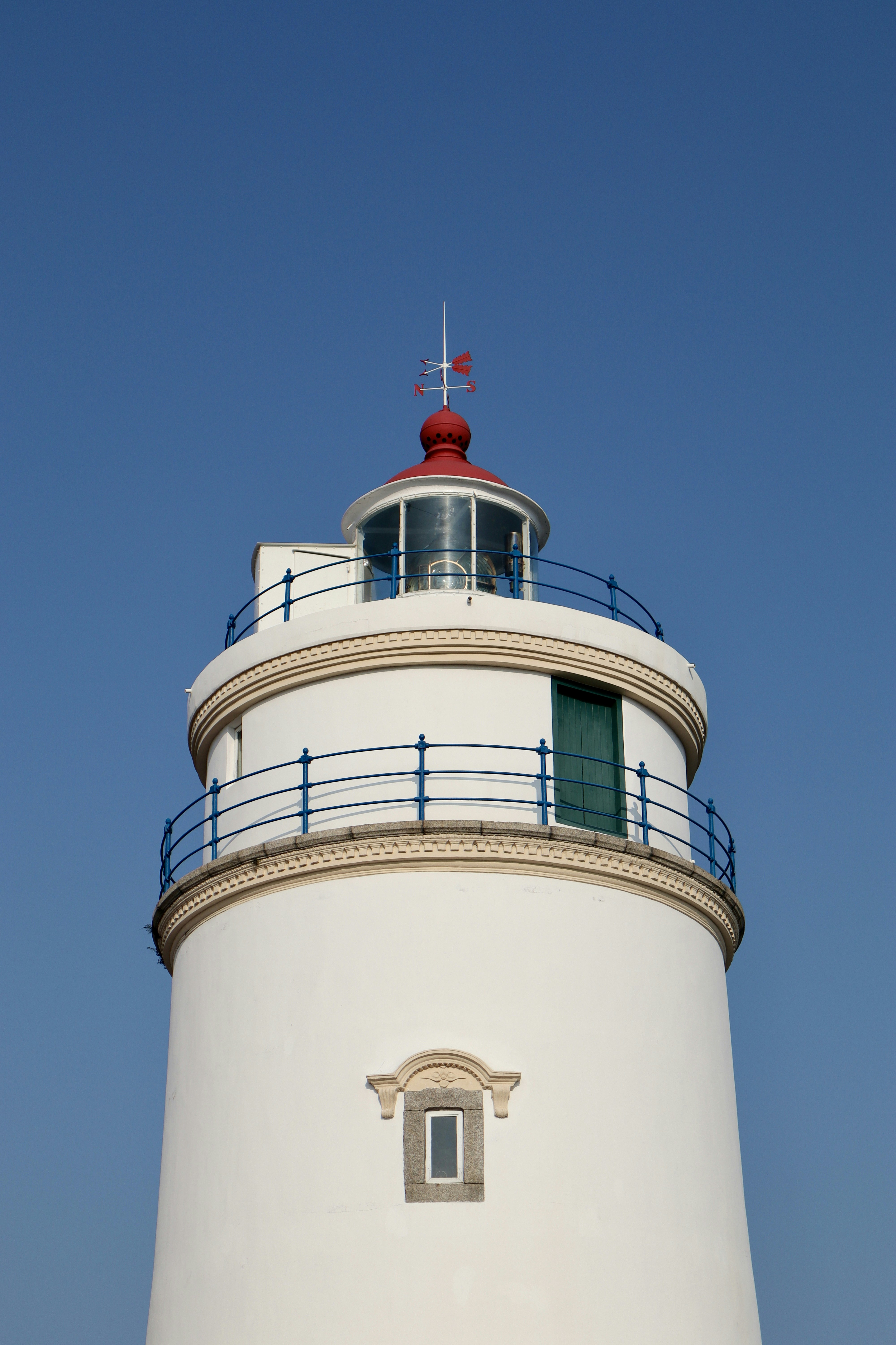 Vertical Beacon: The Lighthouse Tower Pierced by a Clear Blue Sky