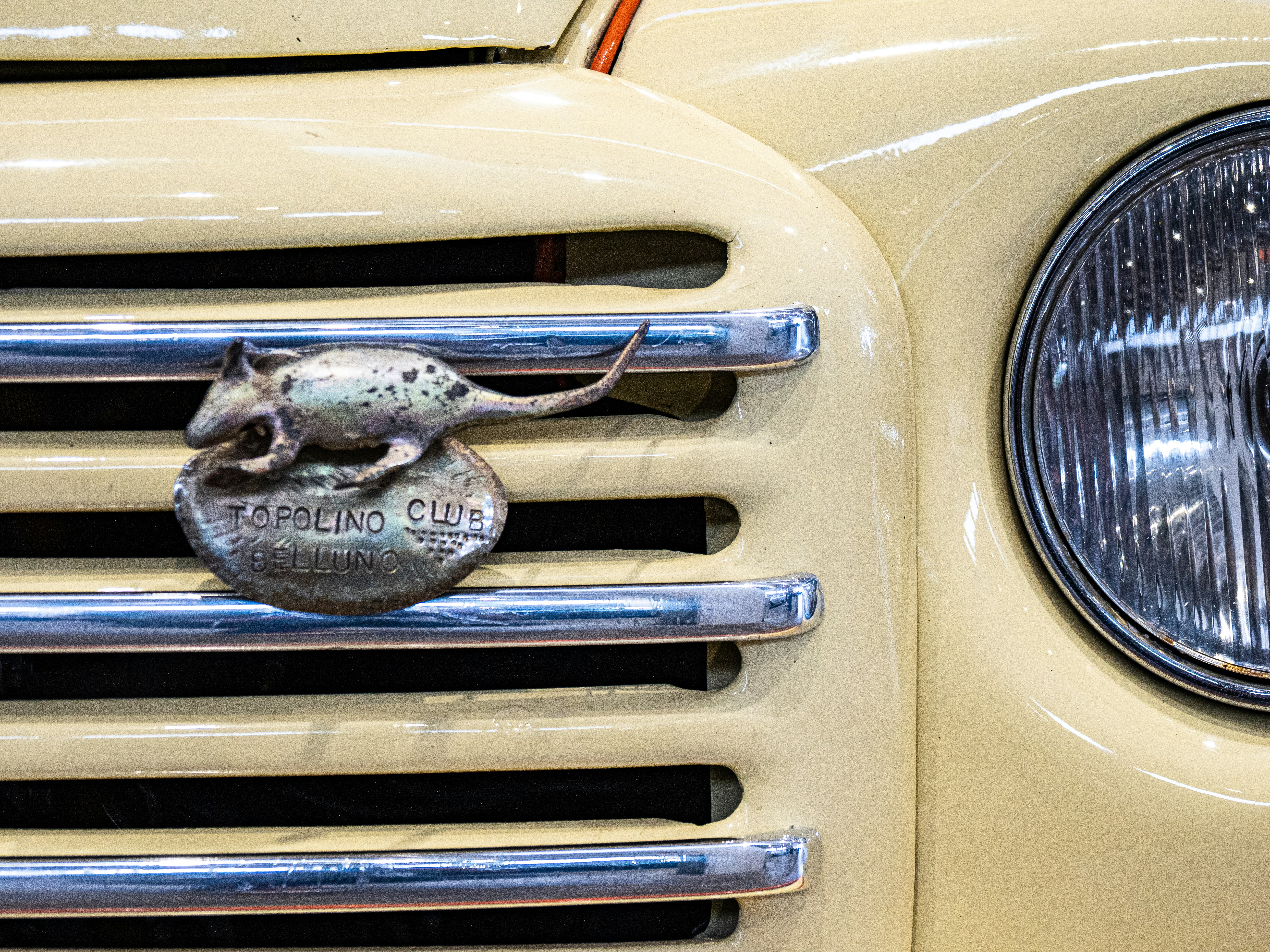 Close-up of a vintage car grille with a mouse emblem.