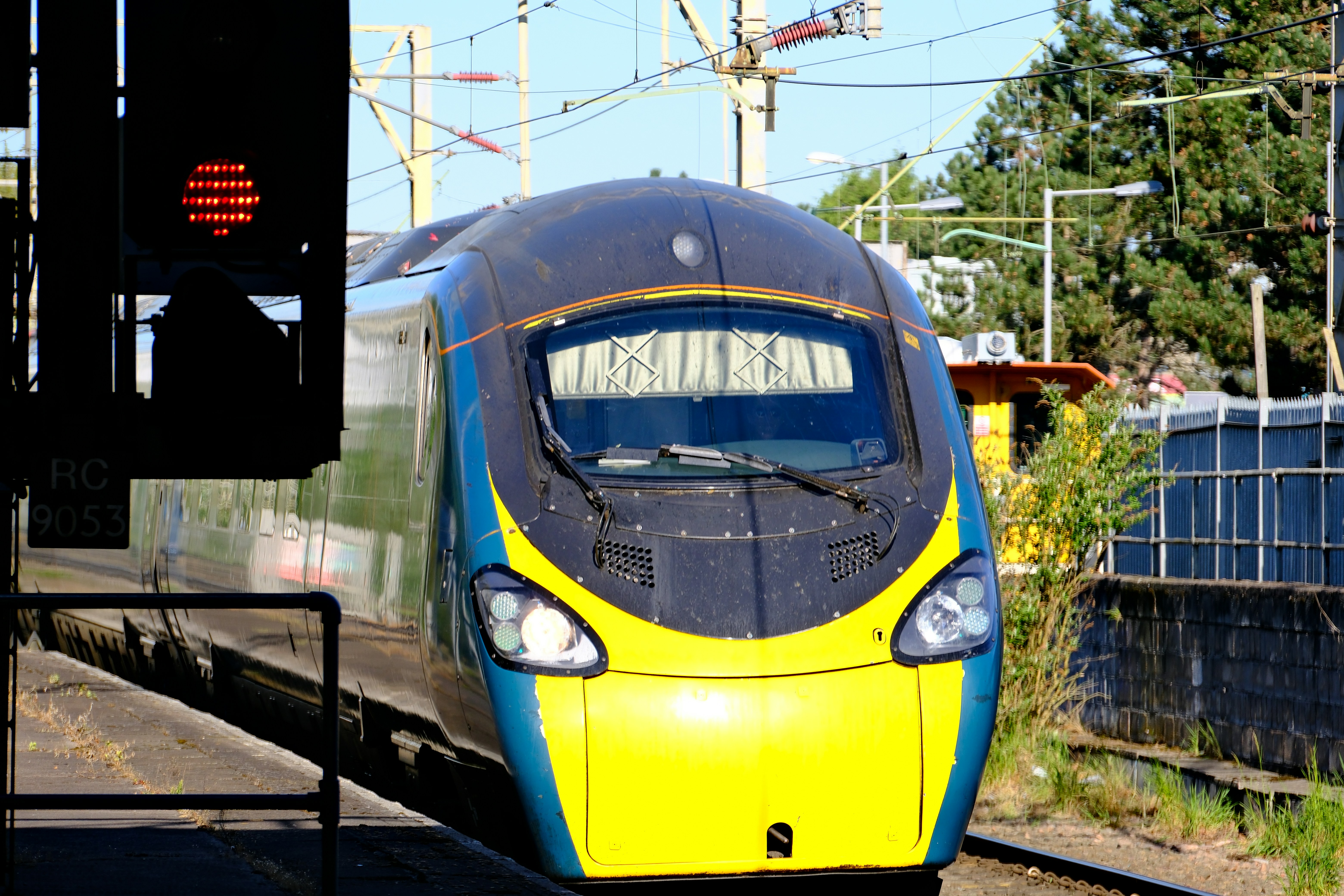 Aurora Express: A yellow-blue speedster faces the platform at dusk-light