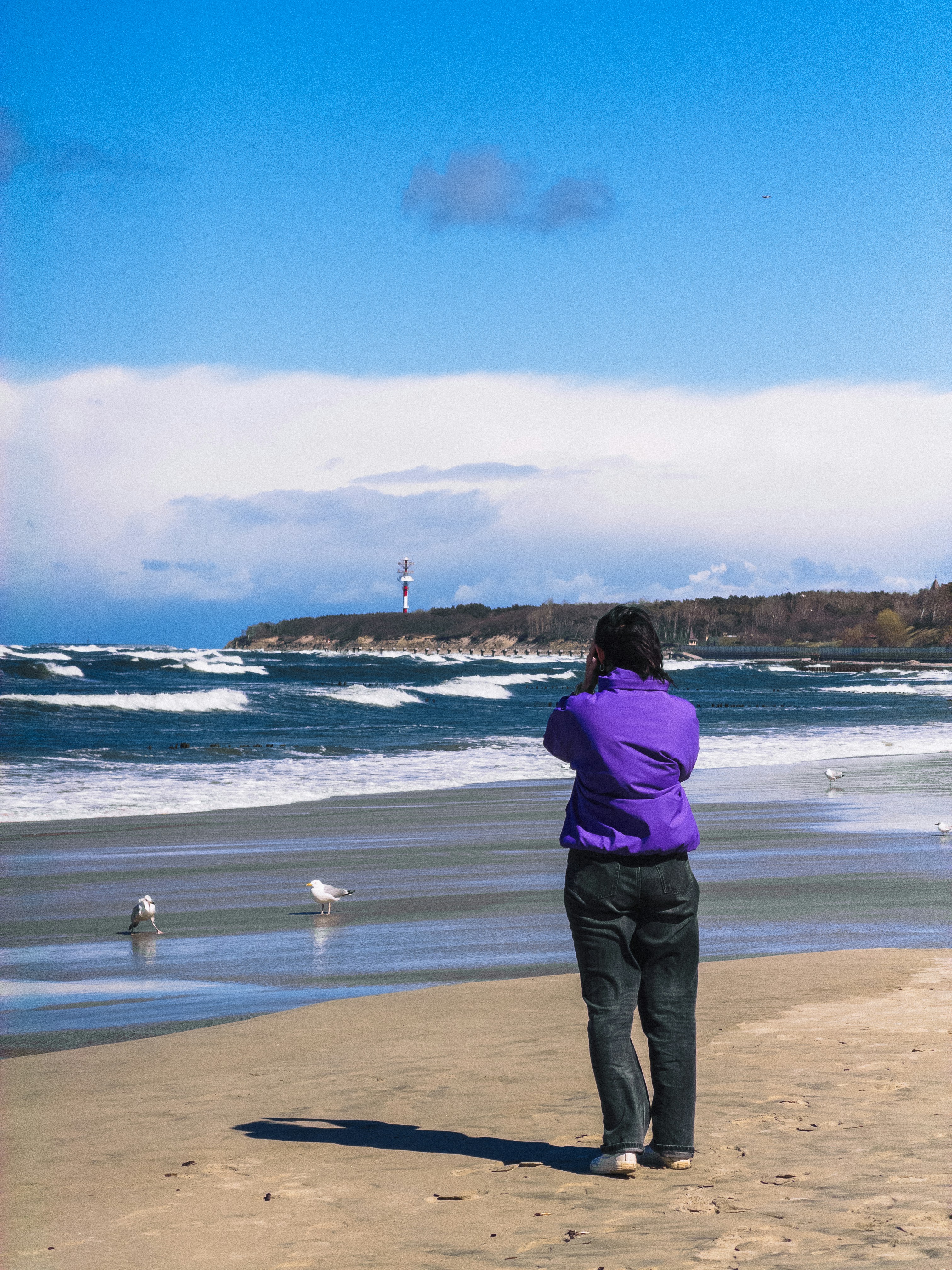 Purple-clad photographer at a windswept seaside