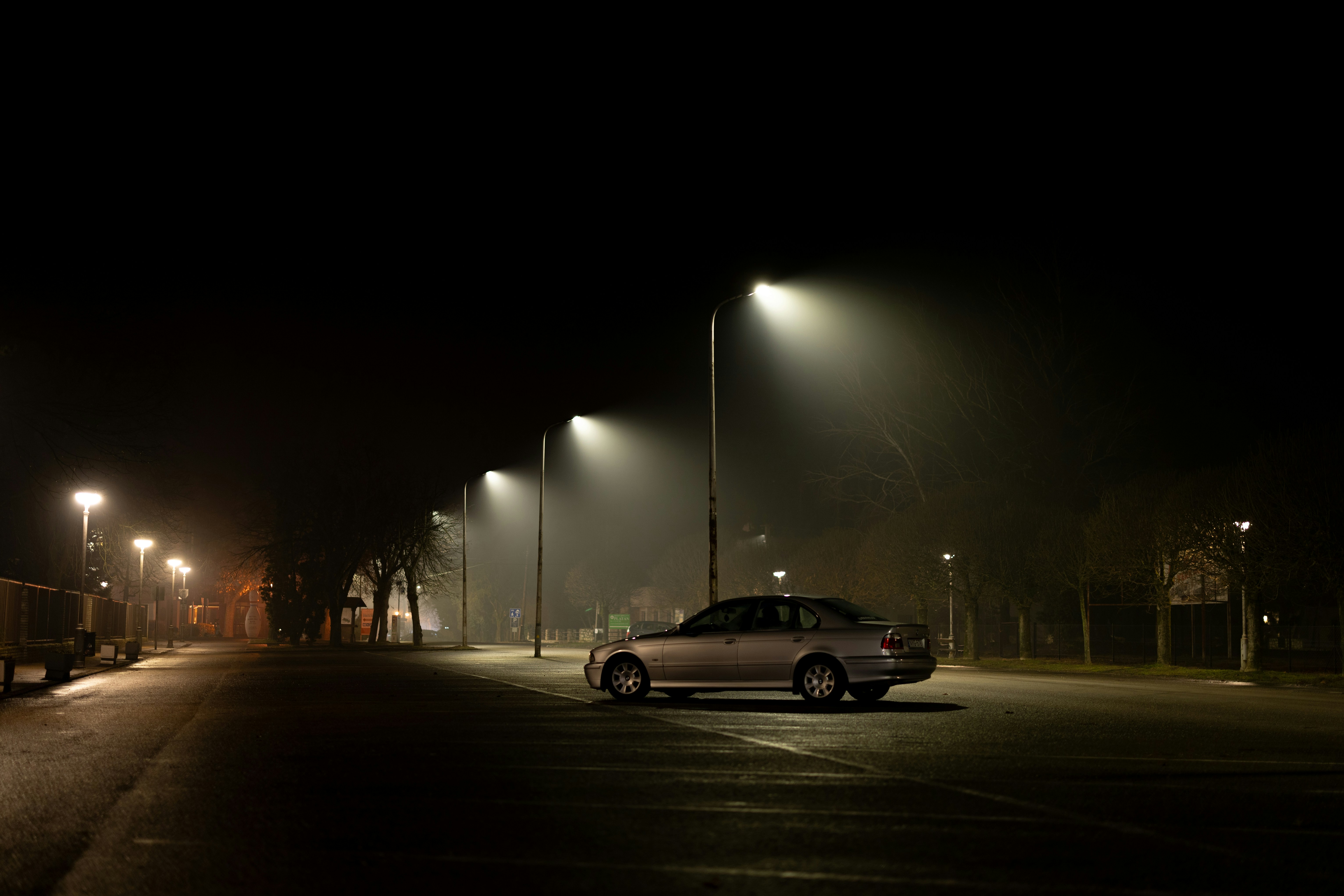 Night-time Parking Lot: A Silver Sedan Anchors the Streetlights' Glow