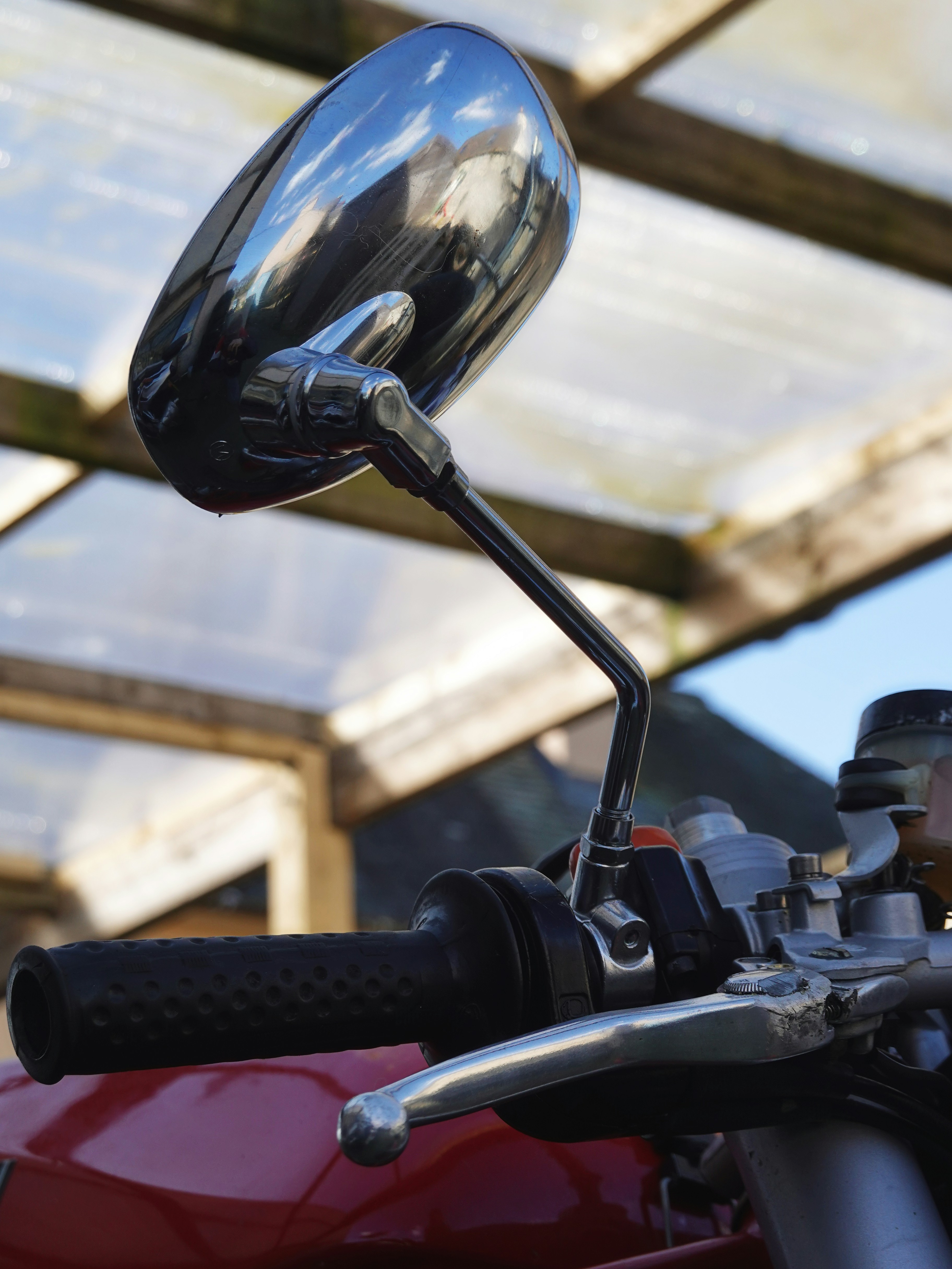 Chrome Mirror, Handlebars, and Sky: Motorcycle Detail in Sunlit Workshop