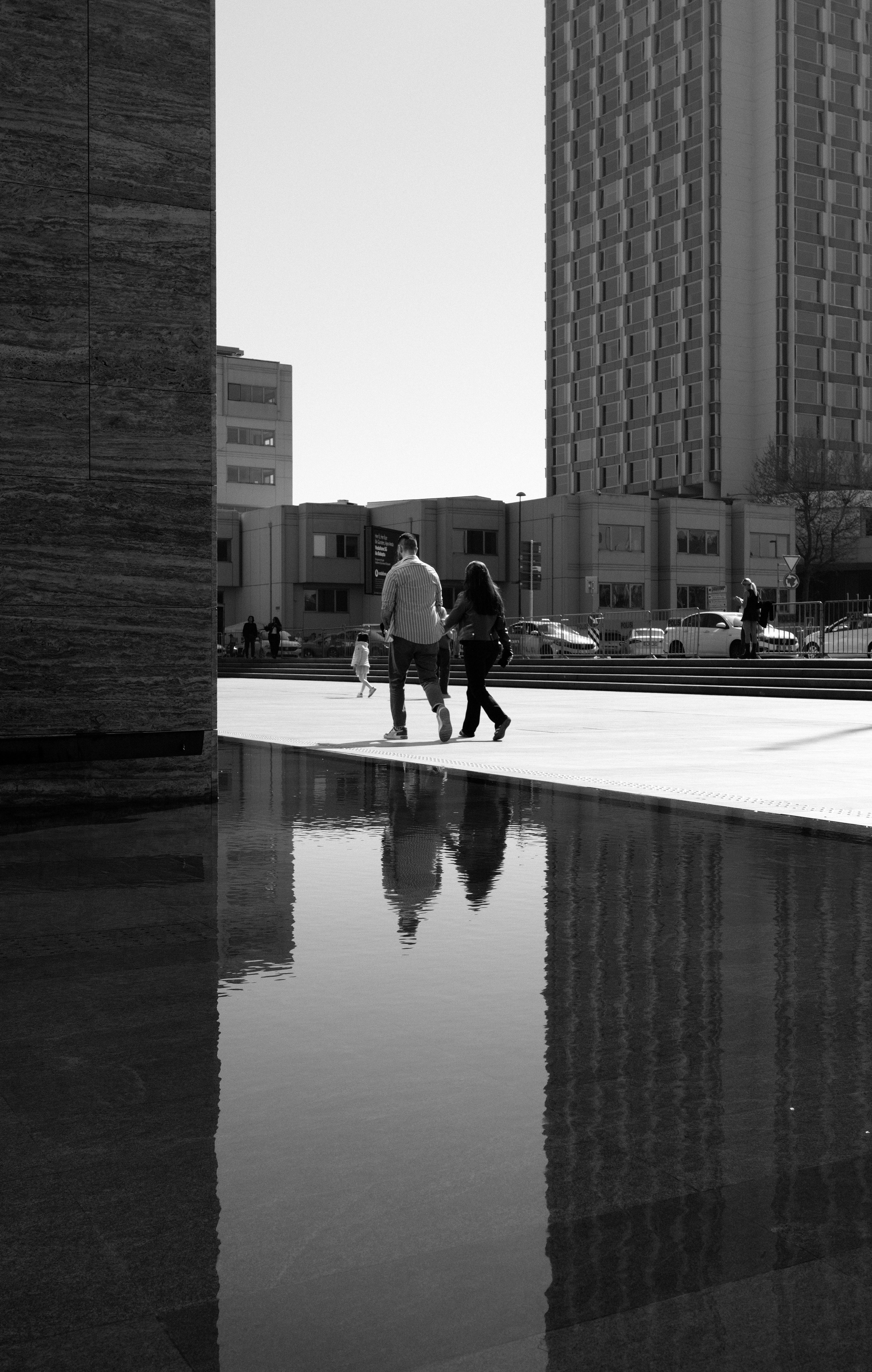 Urban Crossing: silhouette couple and child near reflective pool