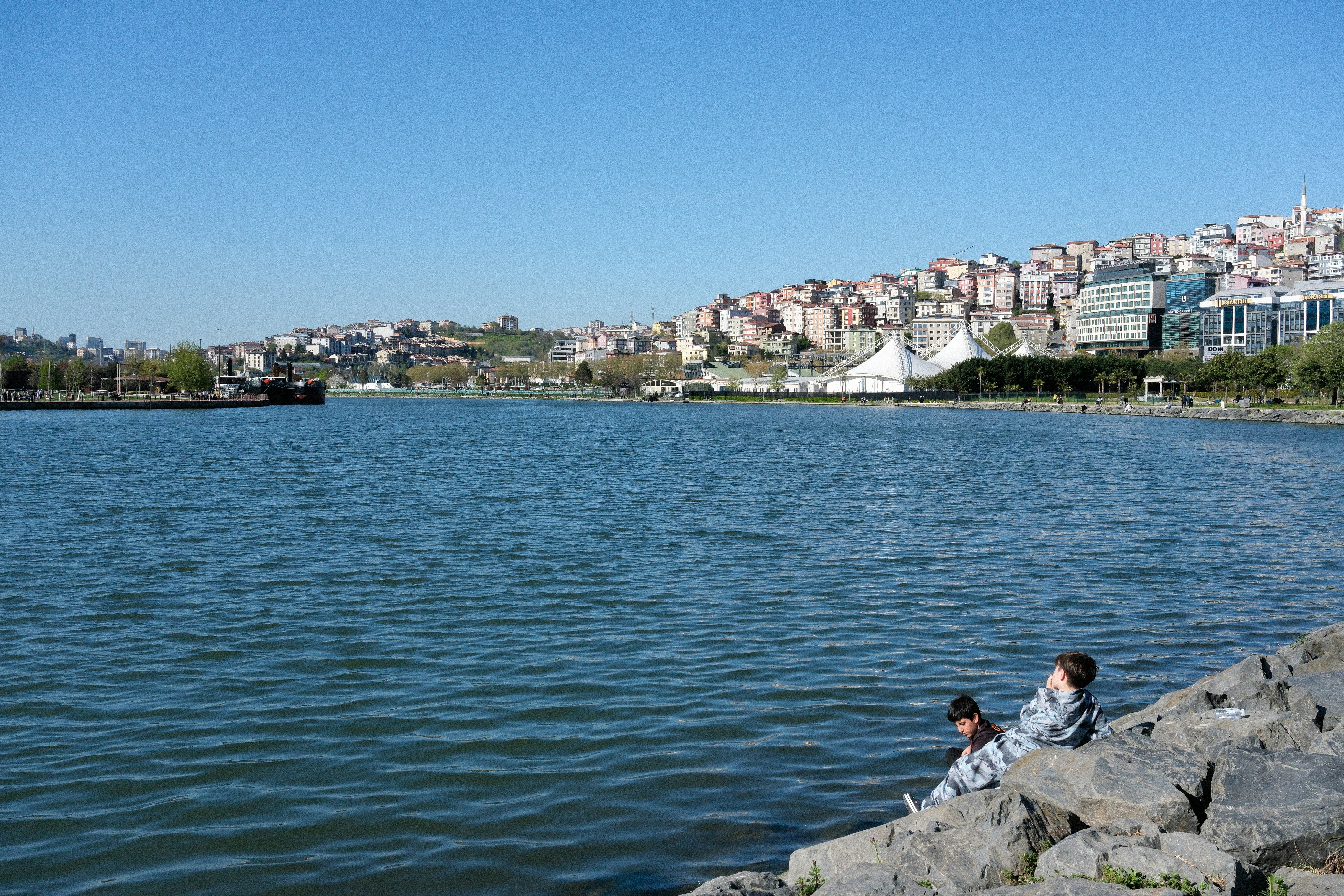 Rugged shoreline and distant hillside town under a clear sky