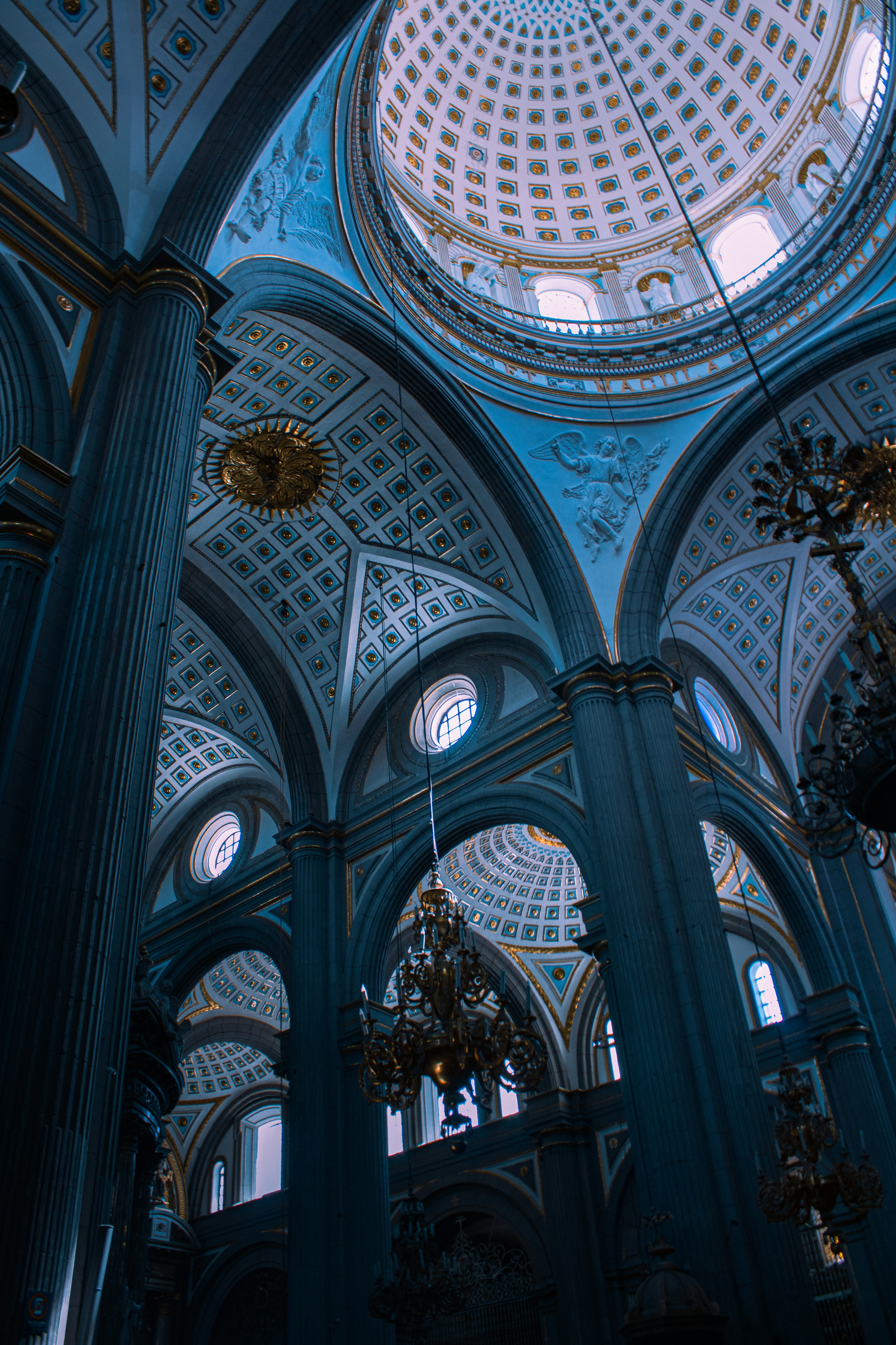 Vaulted Serenity: Blue Hues and Golden Chandeliers in an Immense Dome