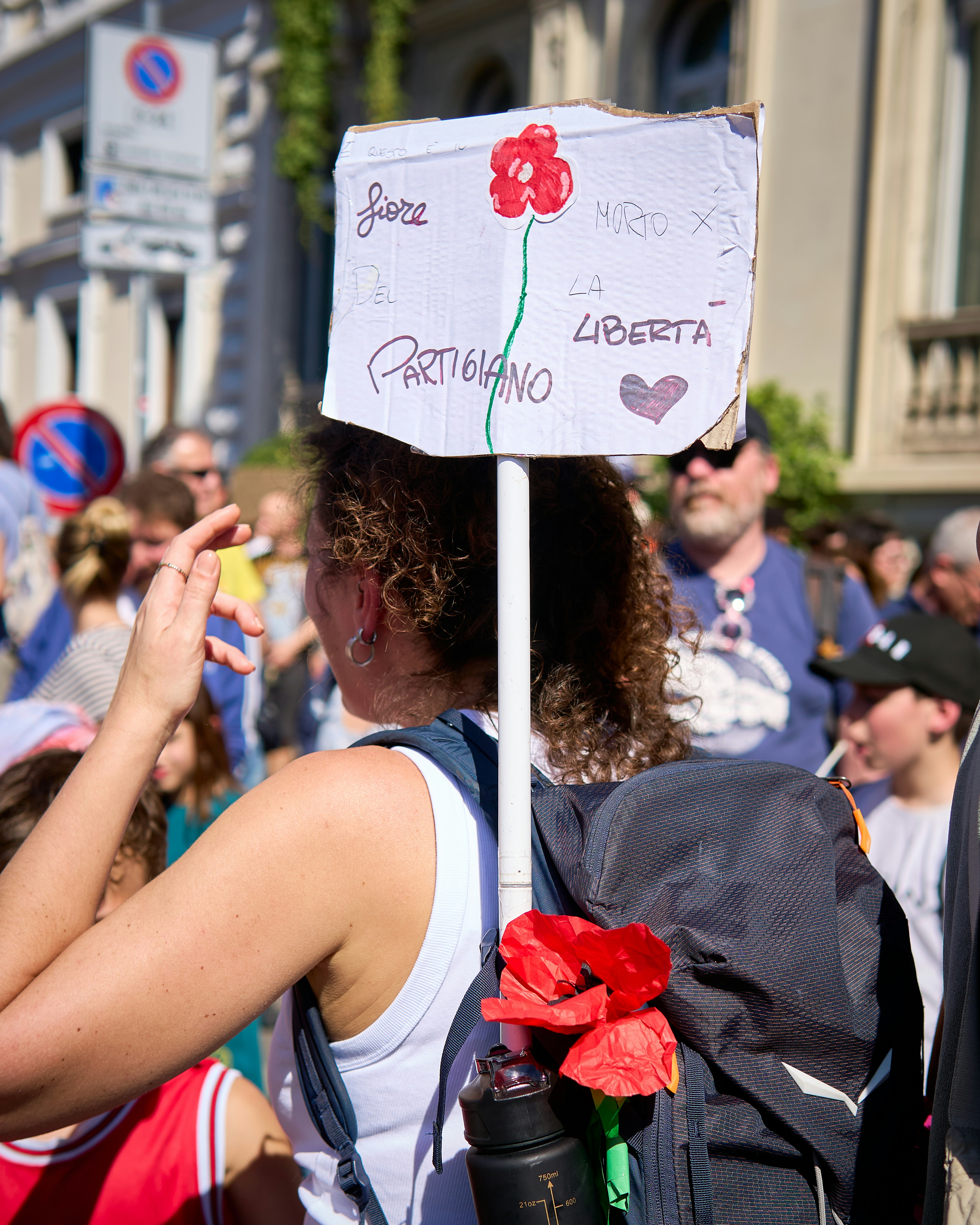 Sign of Hope: A protester holds a handmade placard above a backpack in a sunlit street crowd