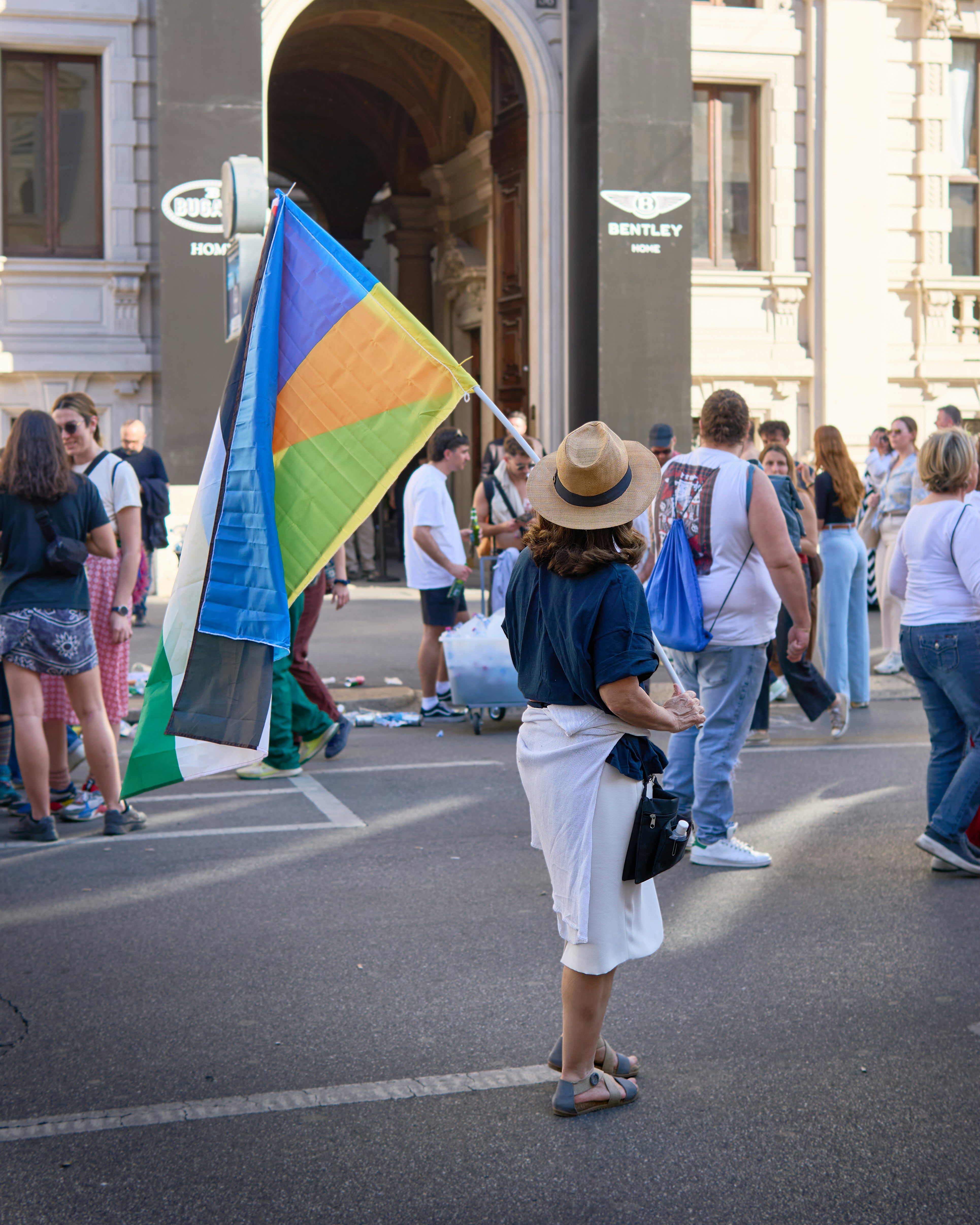 Pride Banner and Hat: A Crowd Before a Historic Facade