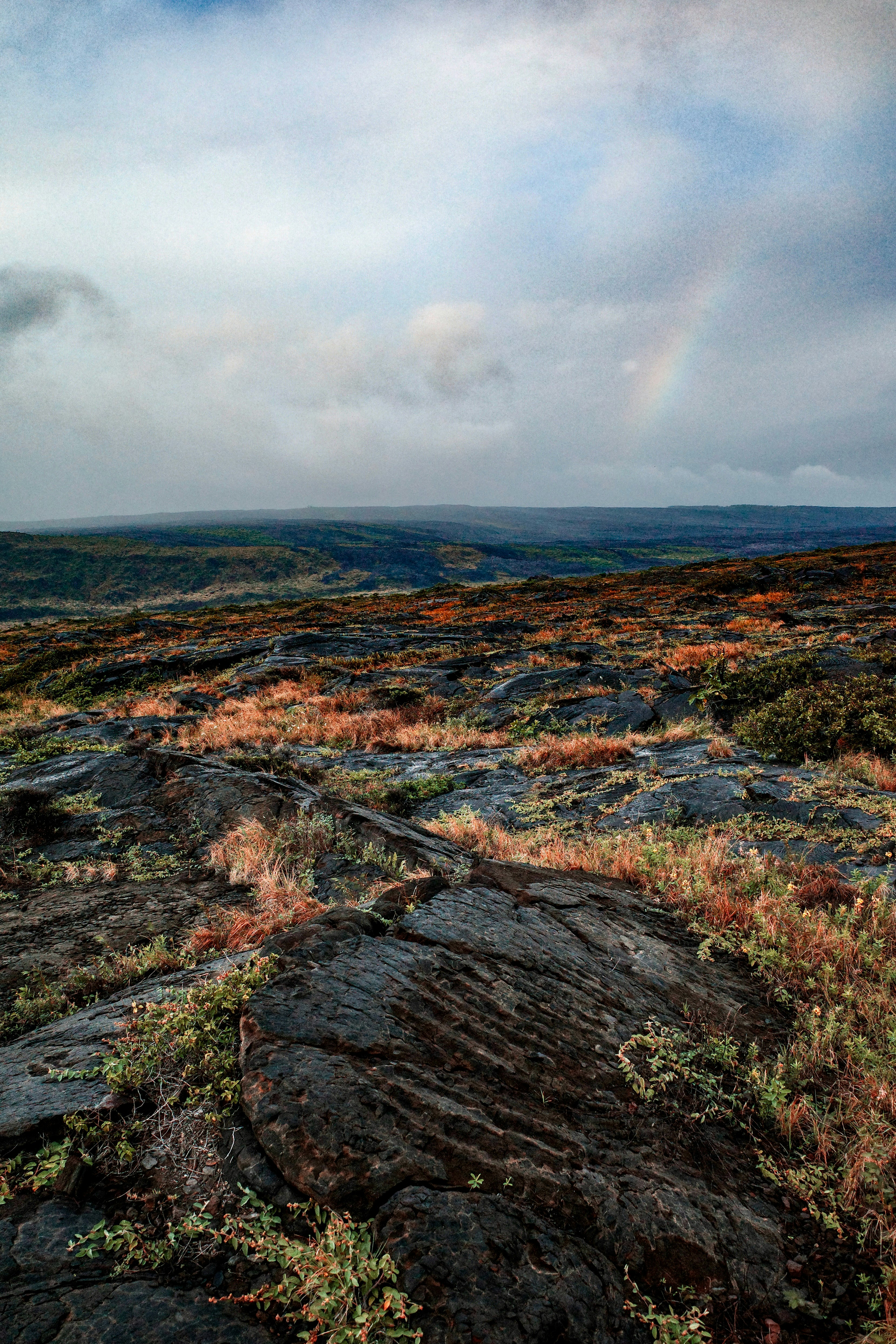 Rainbow over weathered lava plains: quiet horizon and rugged foreground