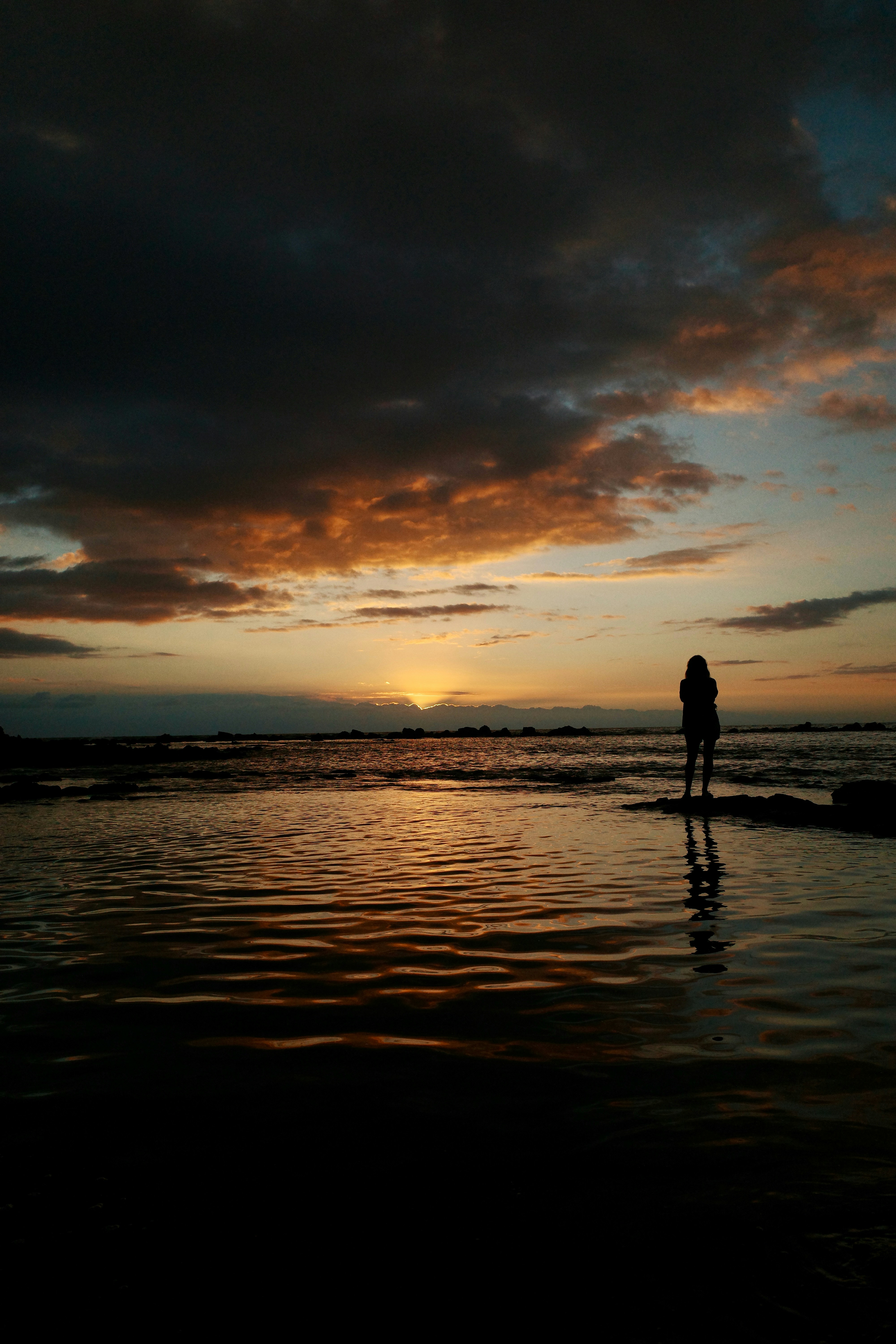 Silhouette at Sunset: lone figure near tidal glow