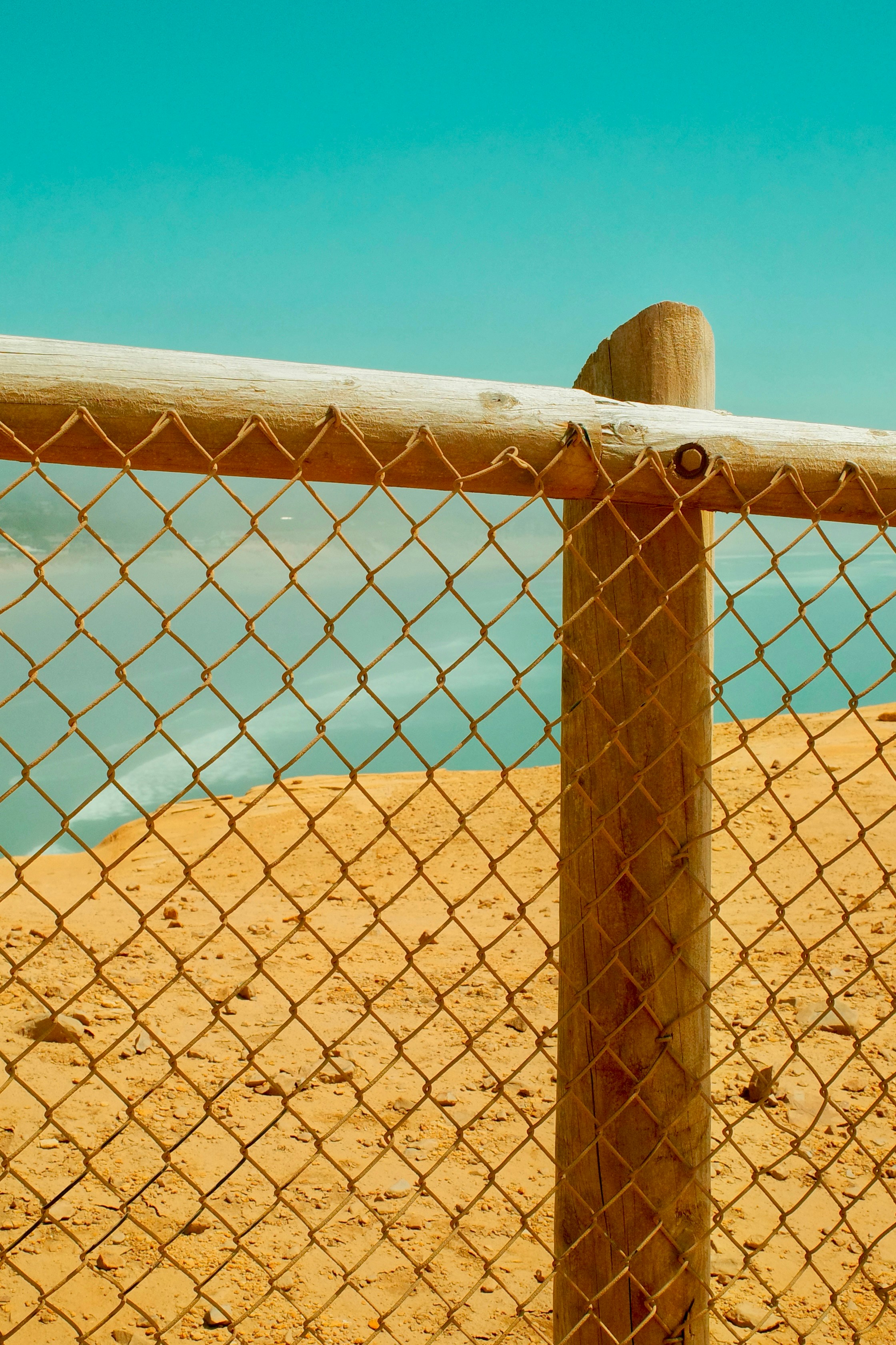 Fence of Light: A Sunlit Beach Through Mesh and Wood