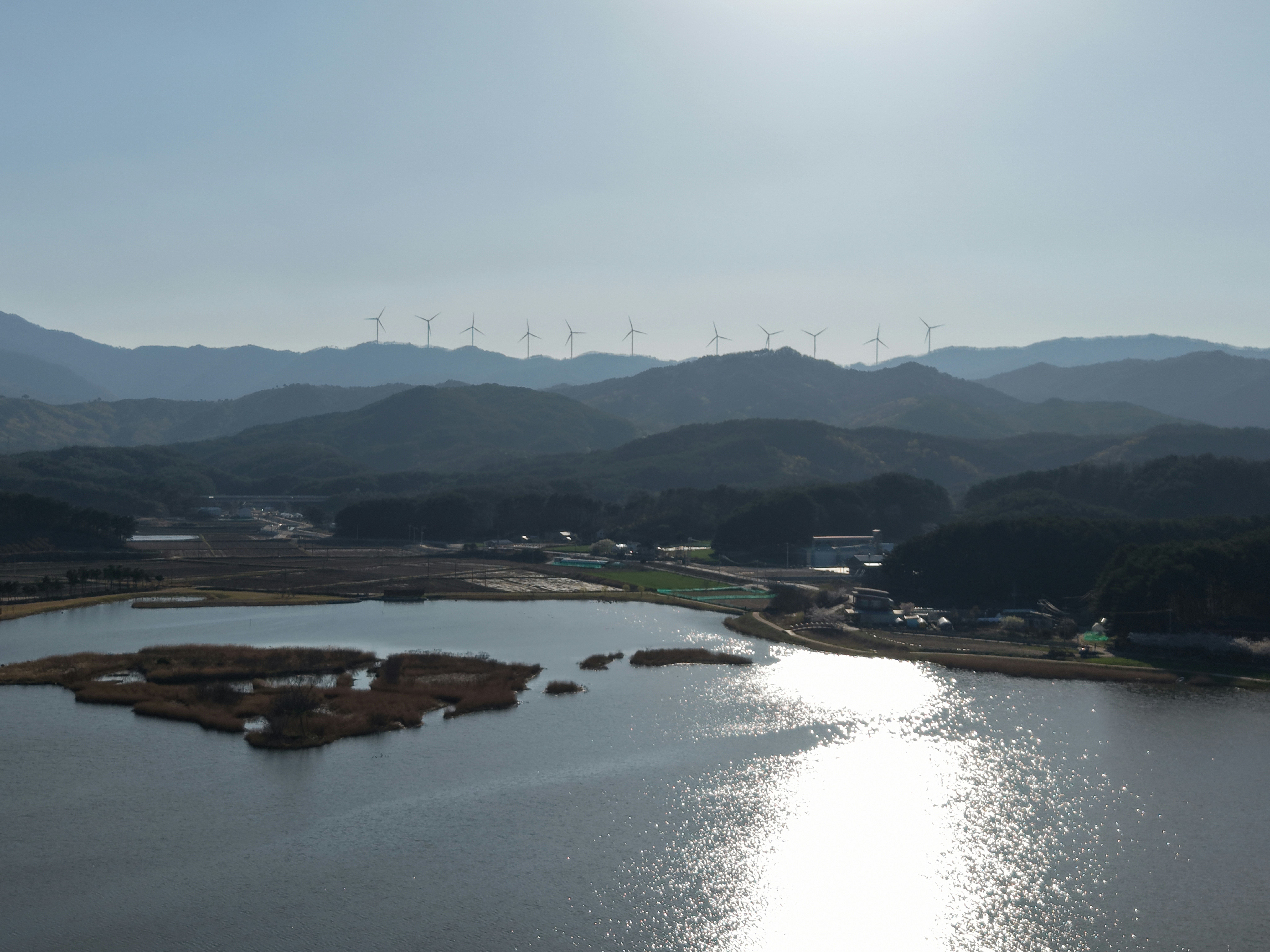 Wind-swept valley: a river sheen with distant turbines