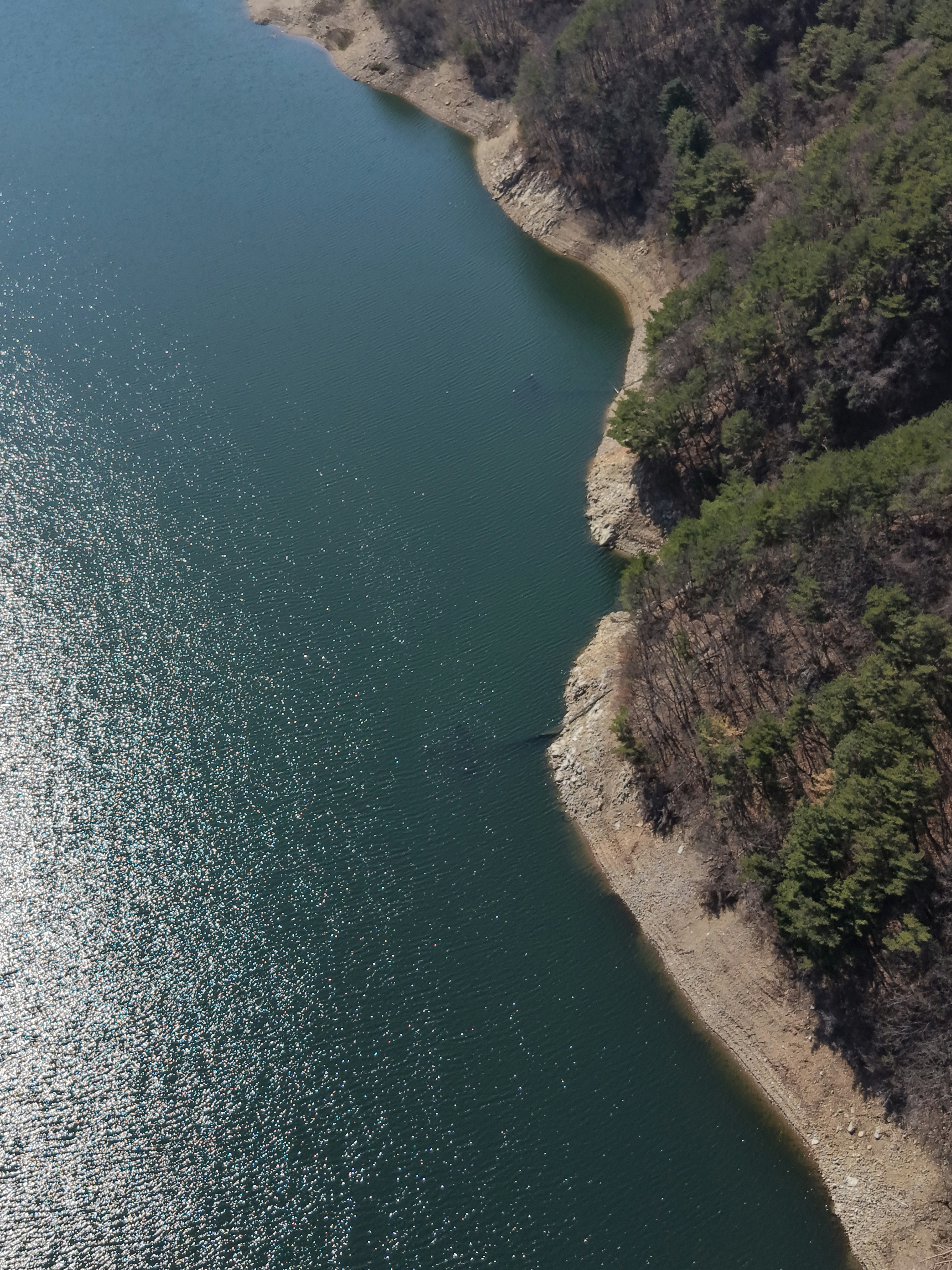 Sunlit shoreline carving through blue depths