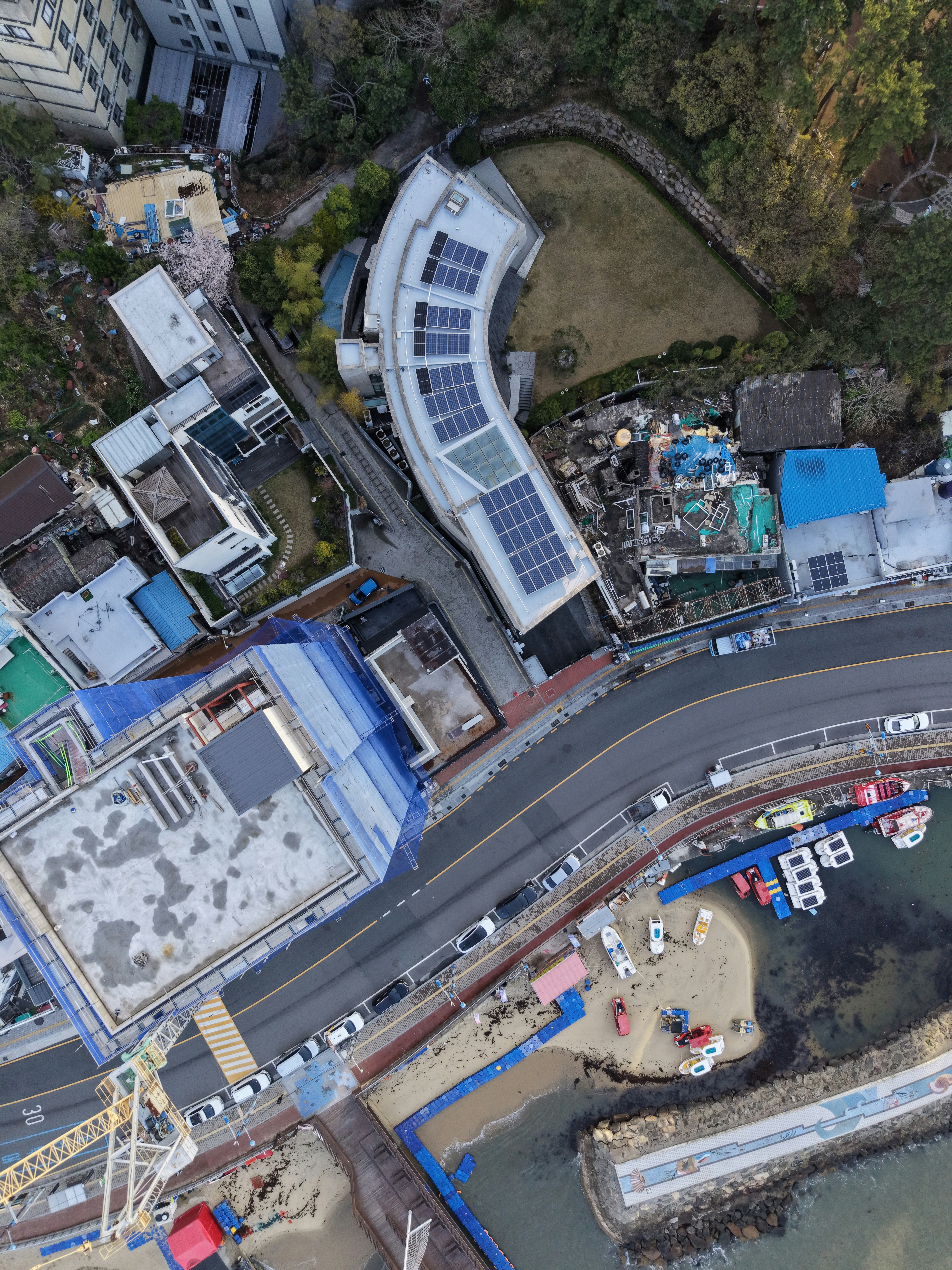 Aerial snapshot of a coastal urban waterfront with winding road and colorful rooftops