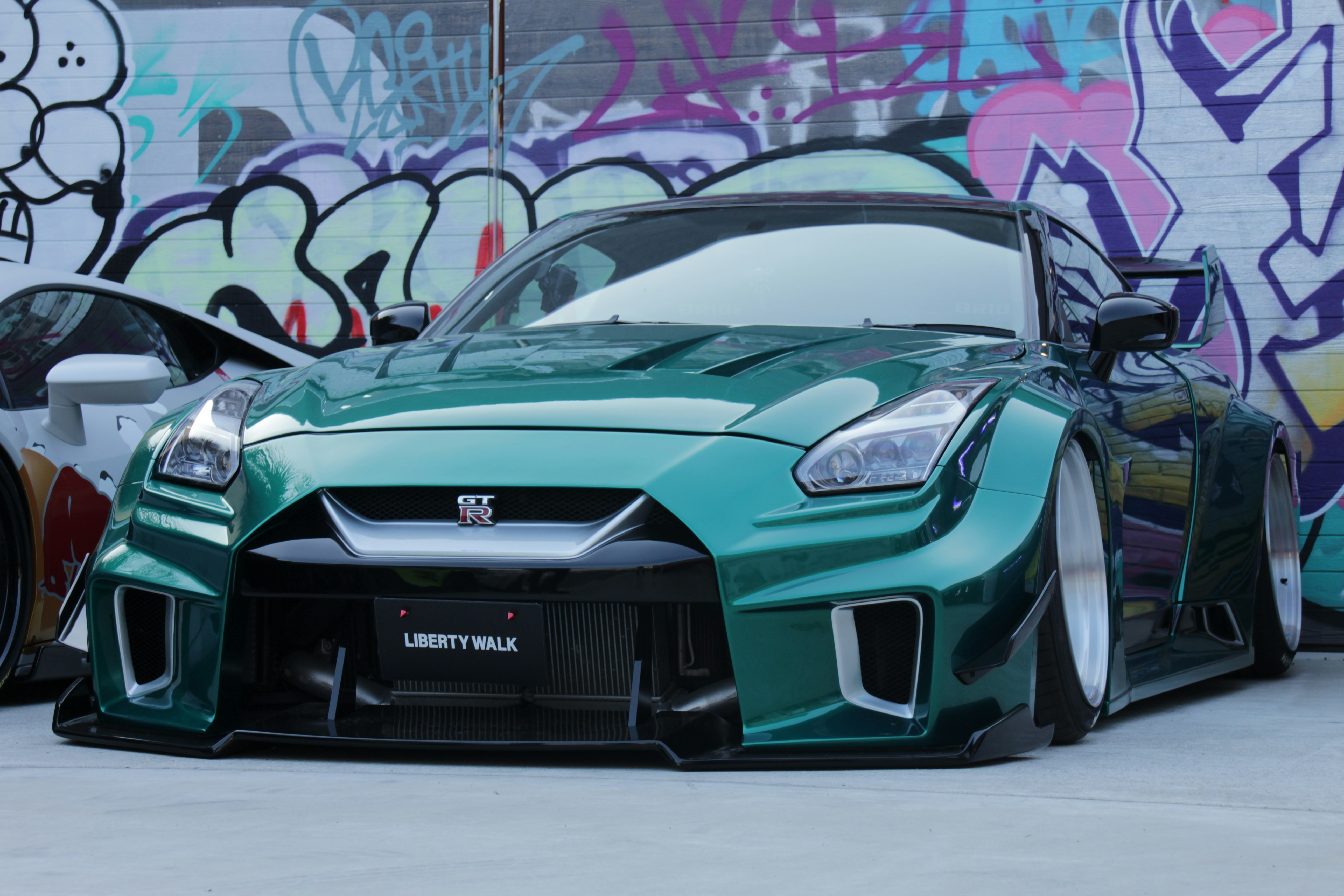 Green GT-R Stance: Low-Slung Power in Front of Graffiti Backdrop