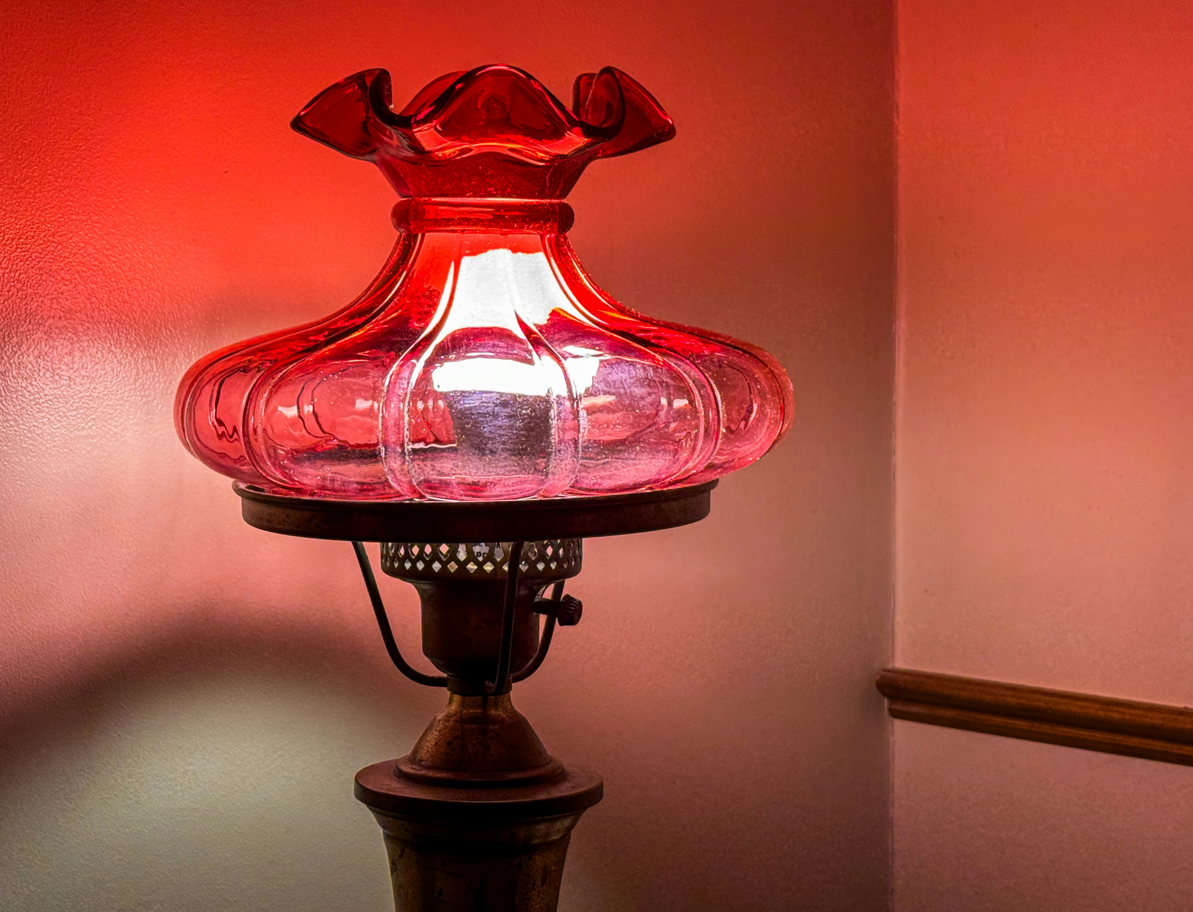 Crimson Glass Lamp Casting a Warm Hue in Dim Corner