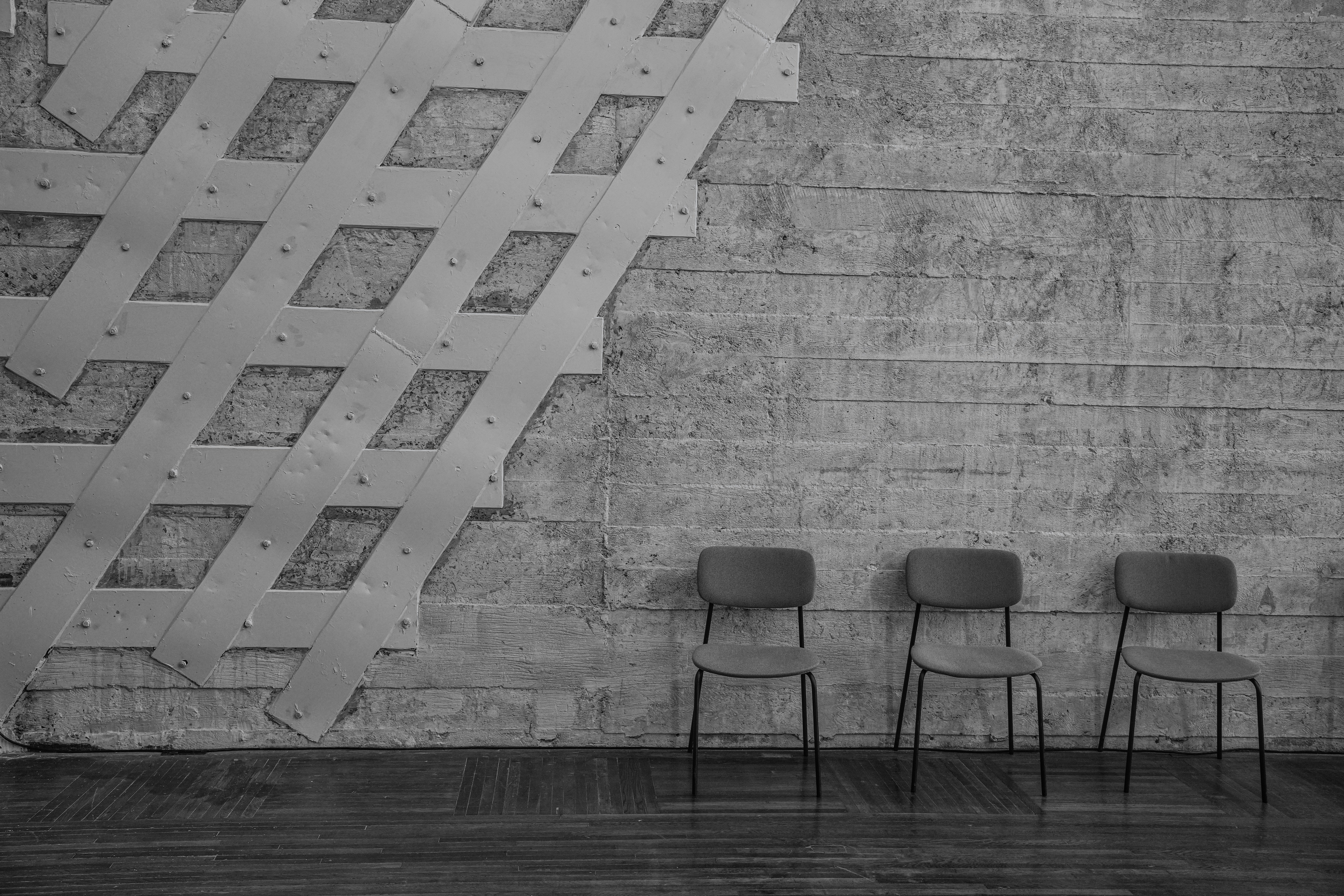 Minimal Row: Four Chairs Against a Geometric Concrete Backdrop