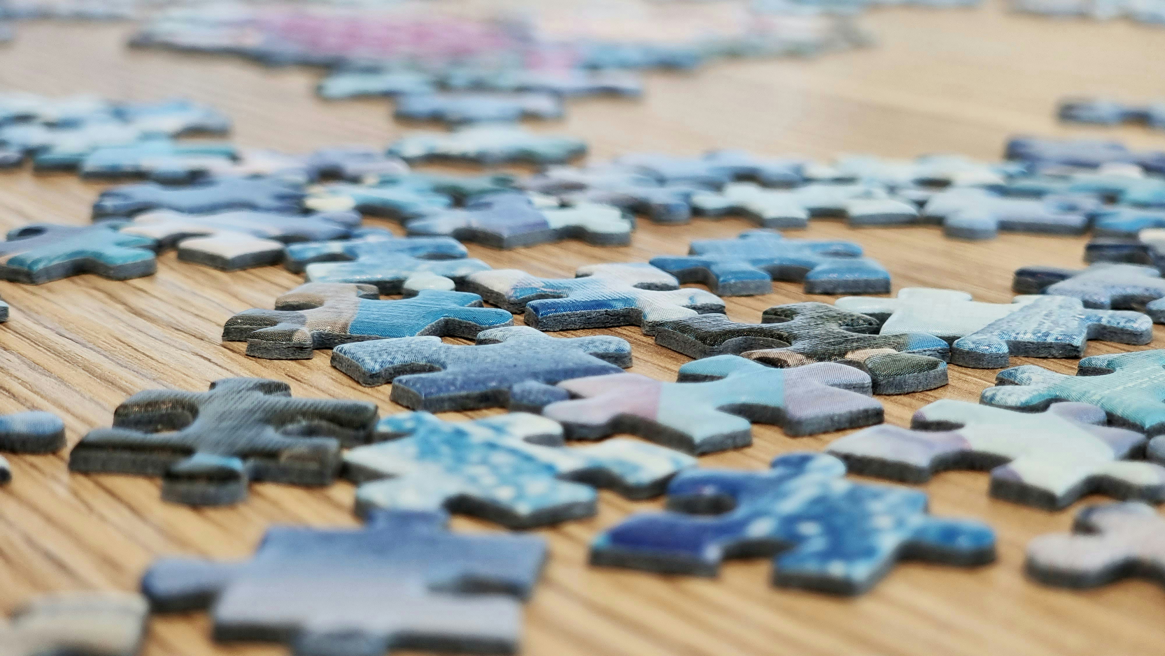 Blue Puzzle Fragments Scatter Across a Warm Wooden Surface