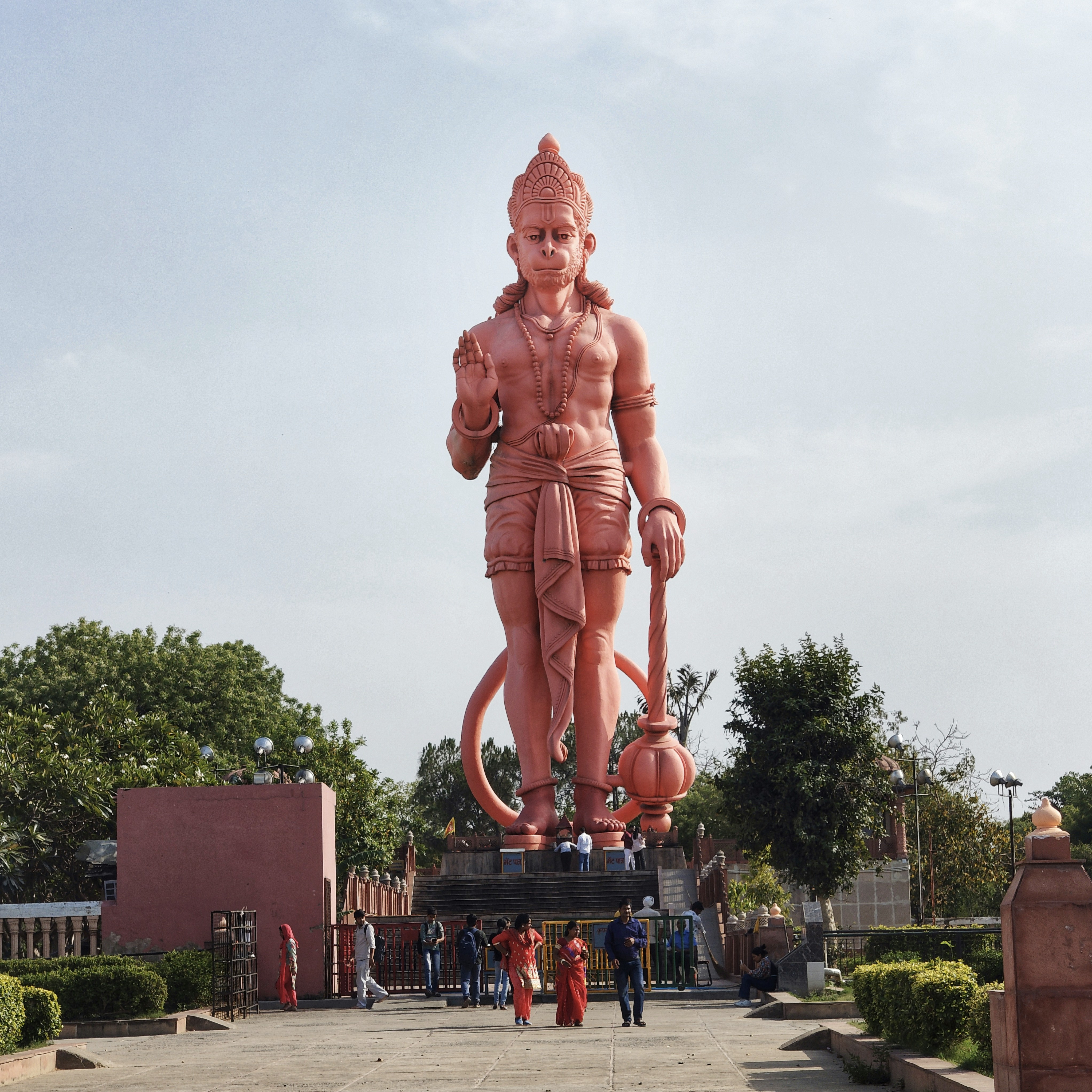 Giant Guardian in the Temple Grounds: A Red-Hued Statue Reaching Toward the Sky