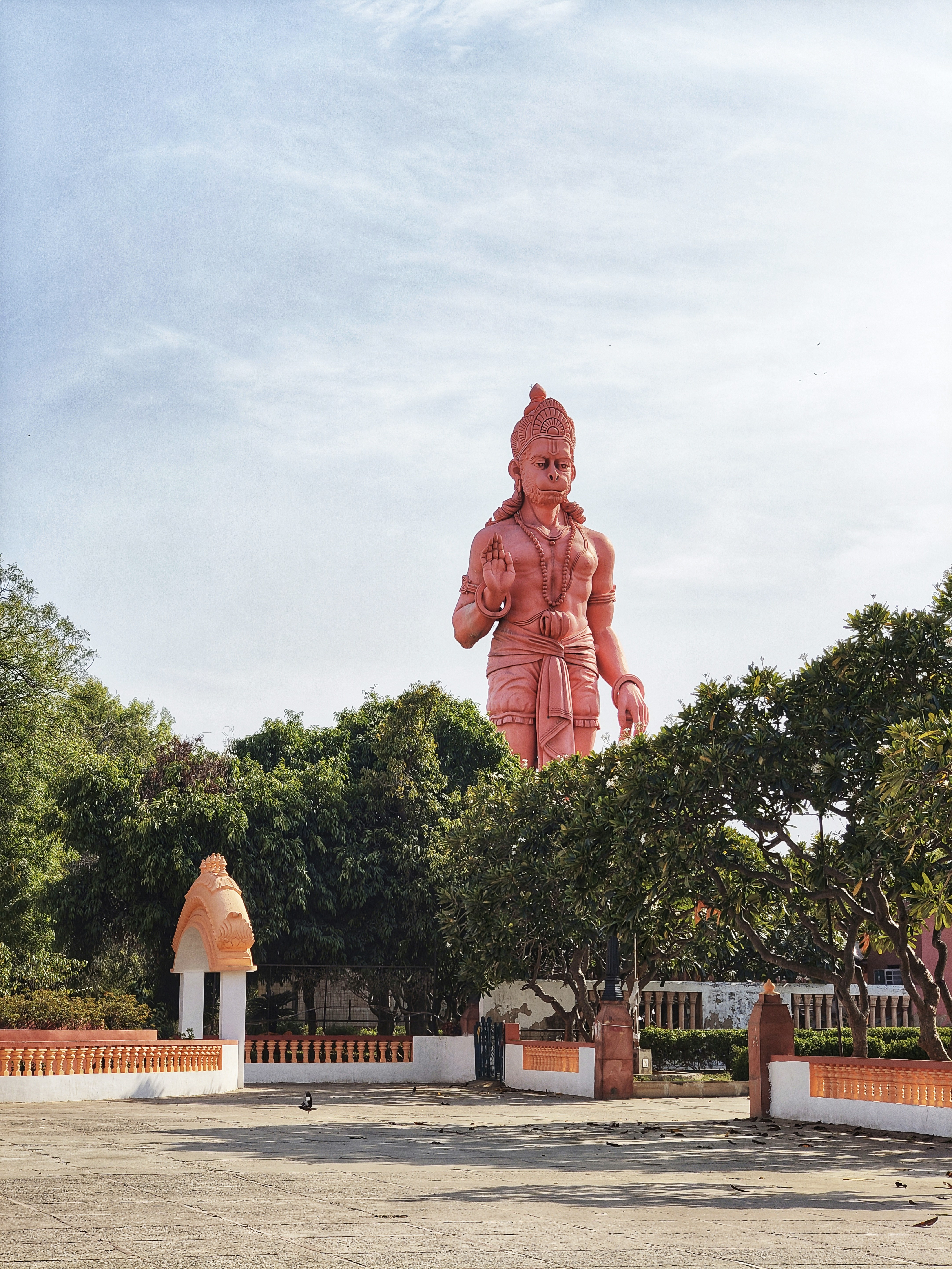 Giant Red Statue Peering Over the Garden Verge